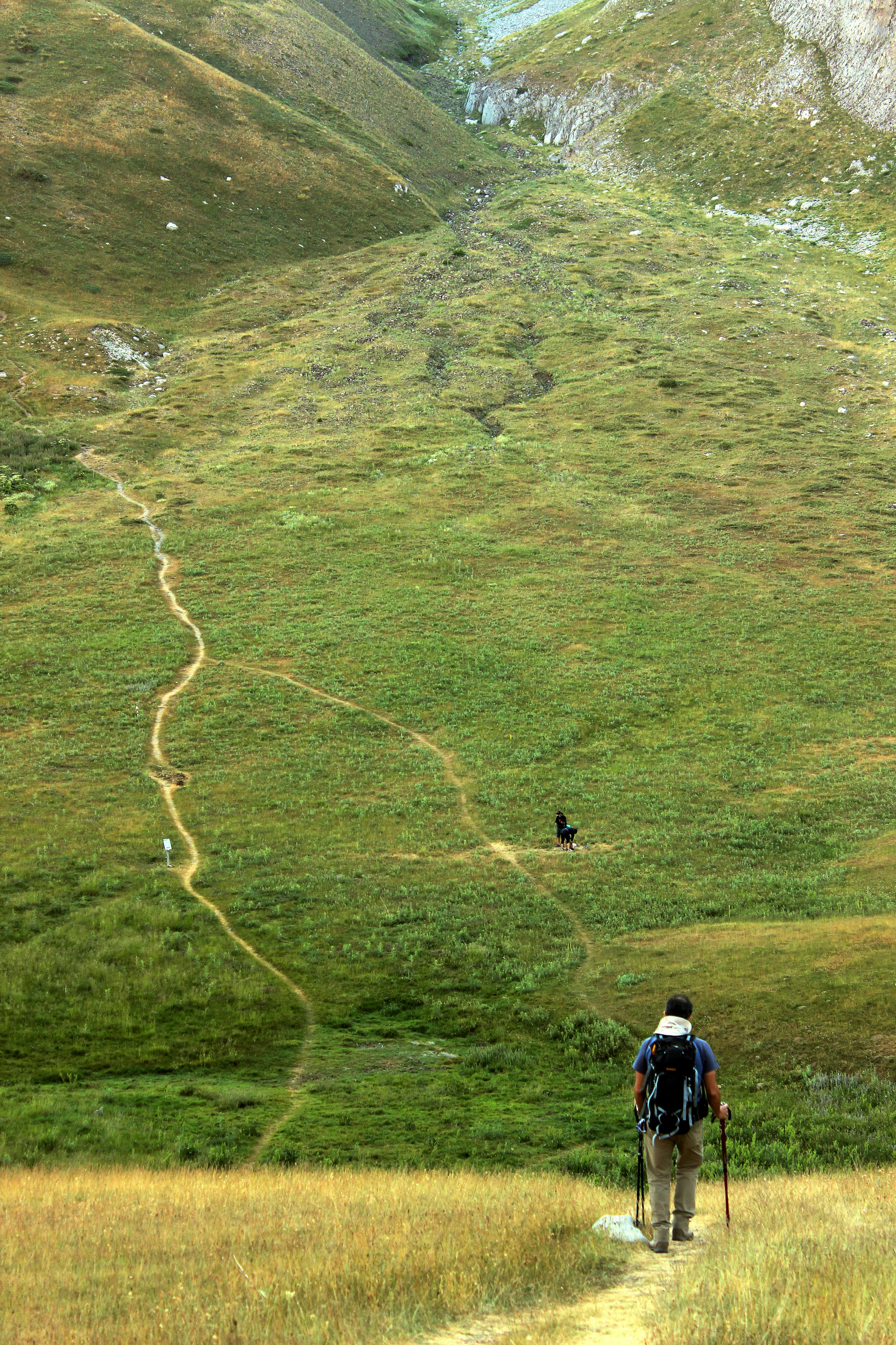 Man Hiking on Path Between Hills · Free Stock Photo