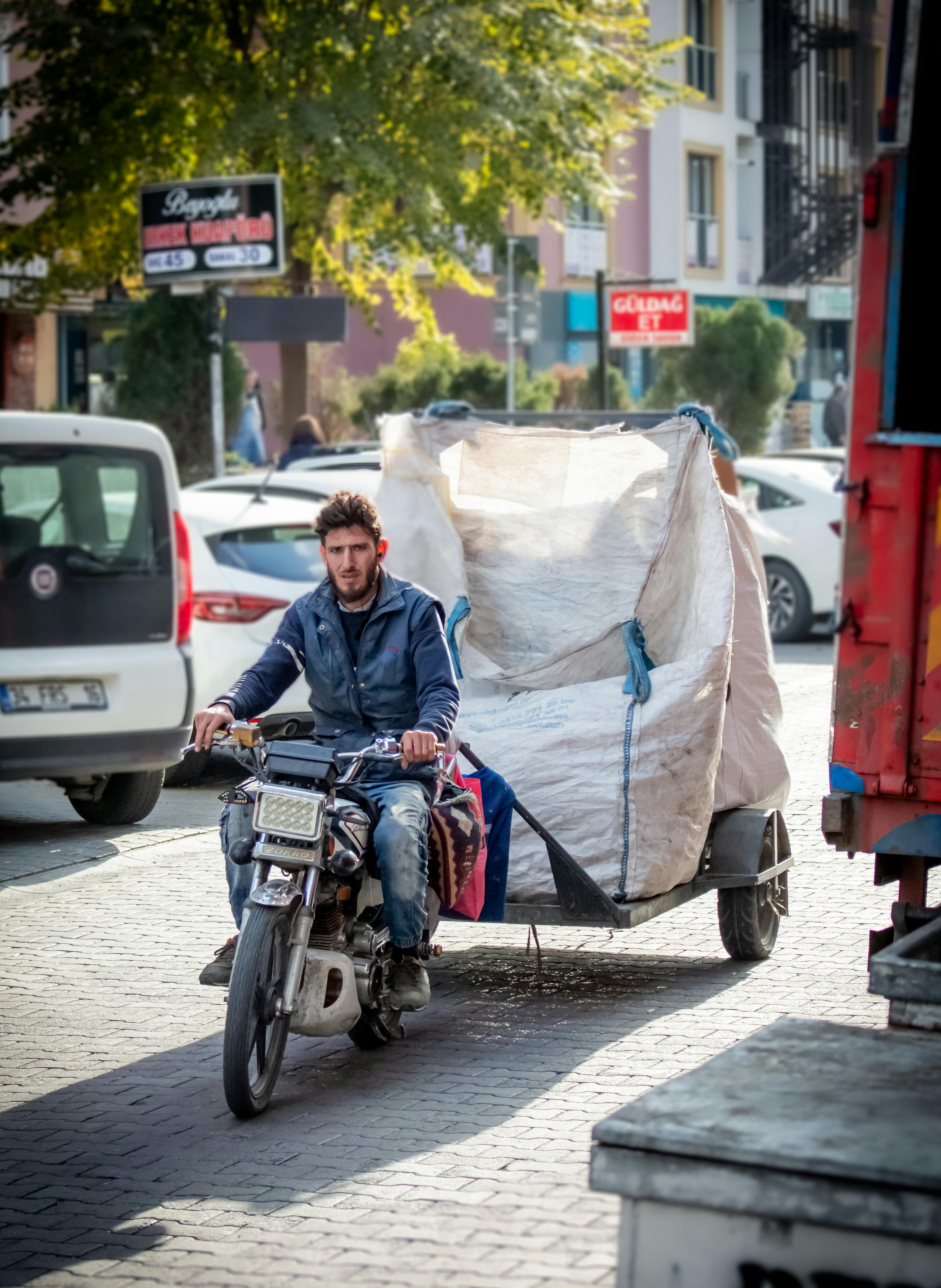 Man Driving Motorcycle with Loaded Trailer on Sidewalk · Free Stock Photo