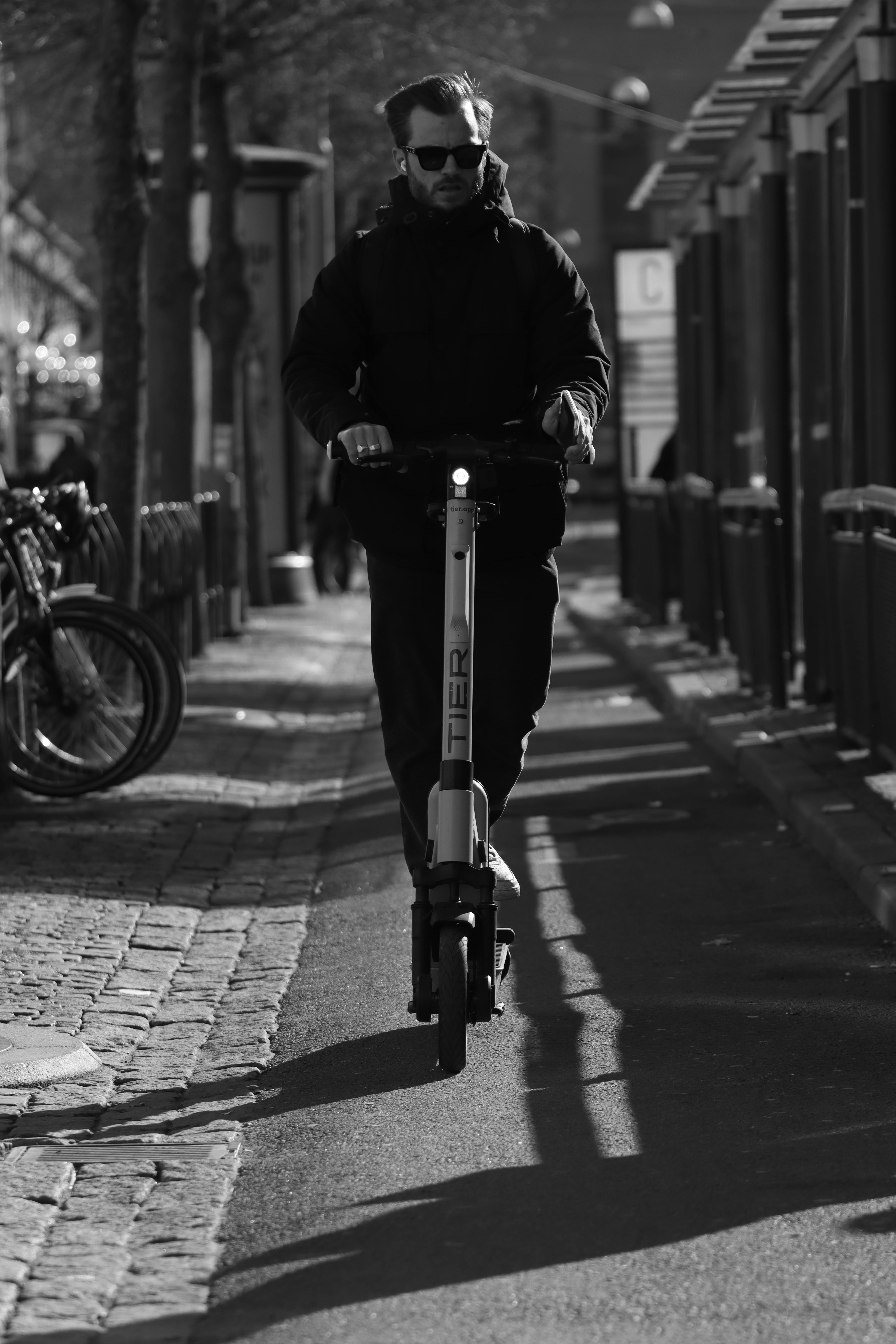 A Grayscale Photo of a Man Riding a Scooter on the Street · Free Stock ...