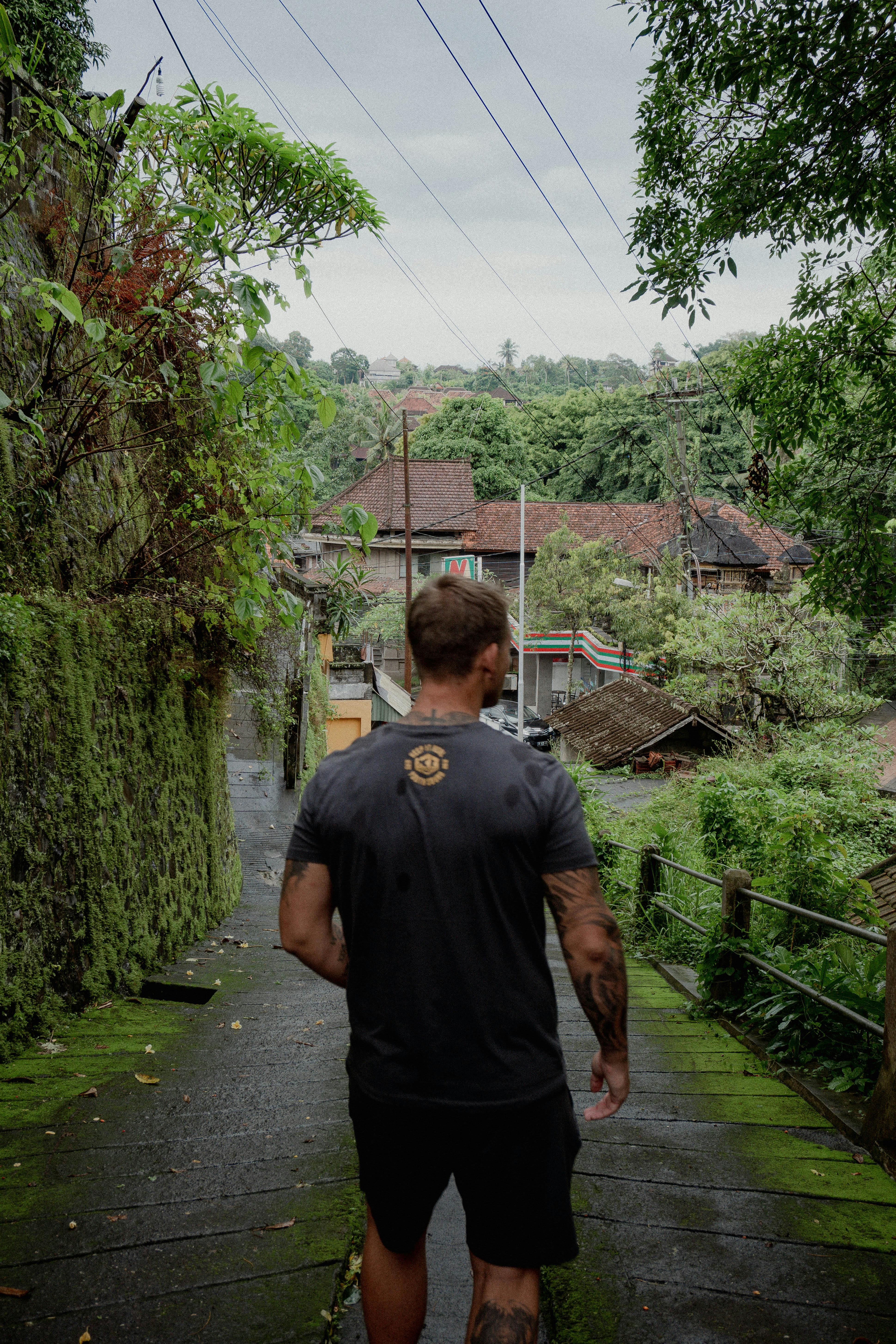 Back View of a Man in Black Shirt Walking Down on a Slanting Road ...
