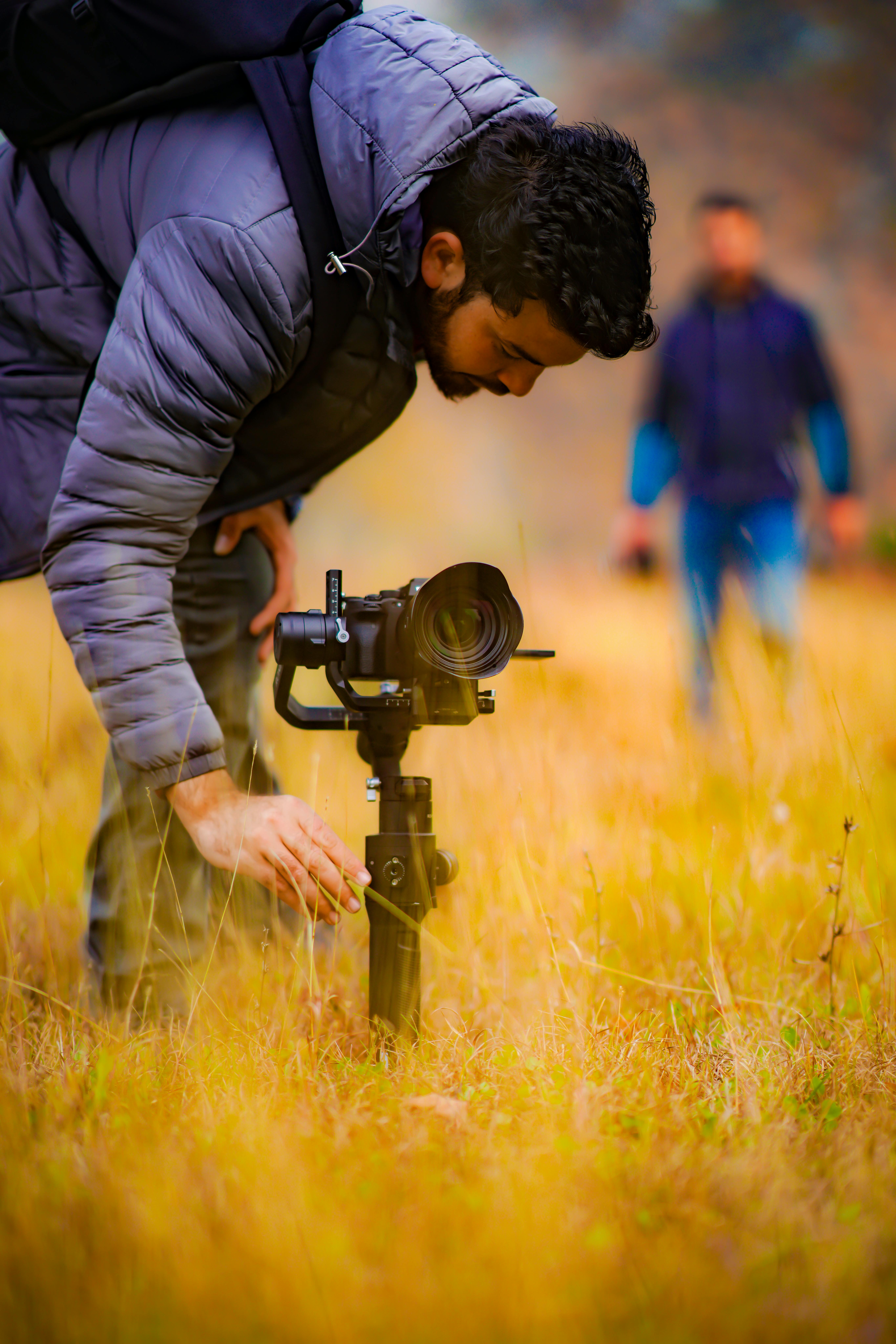 A Man in Puffer Jacket Holding a Camera with Tripod · Free Stock Photo