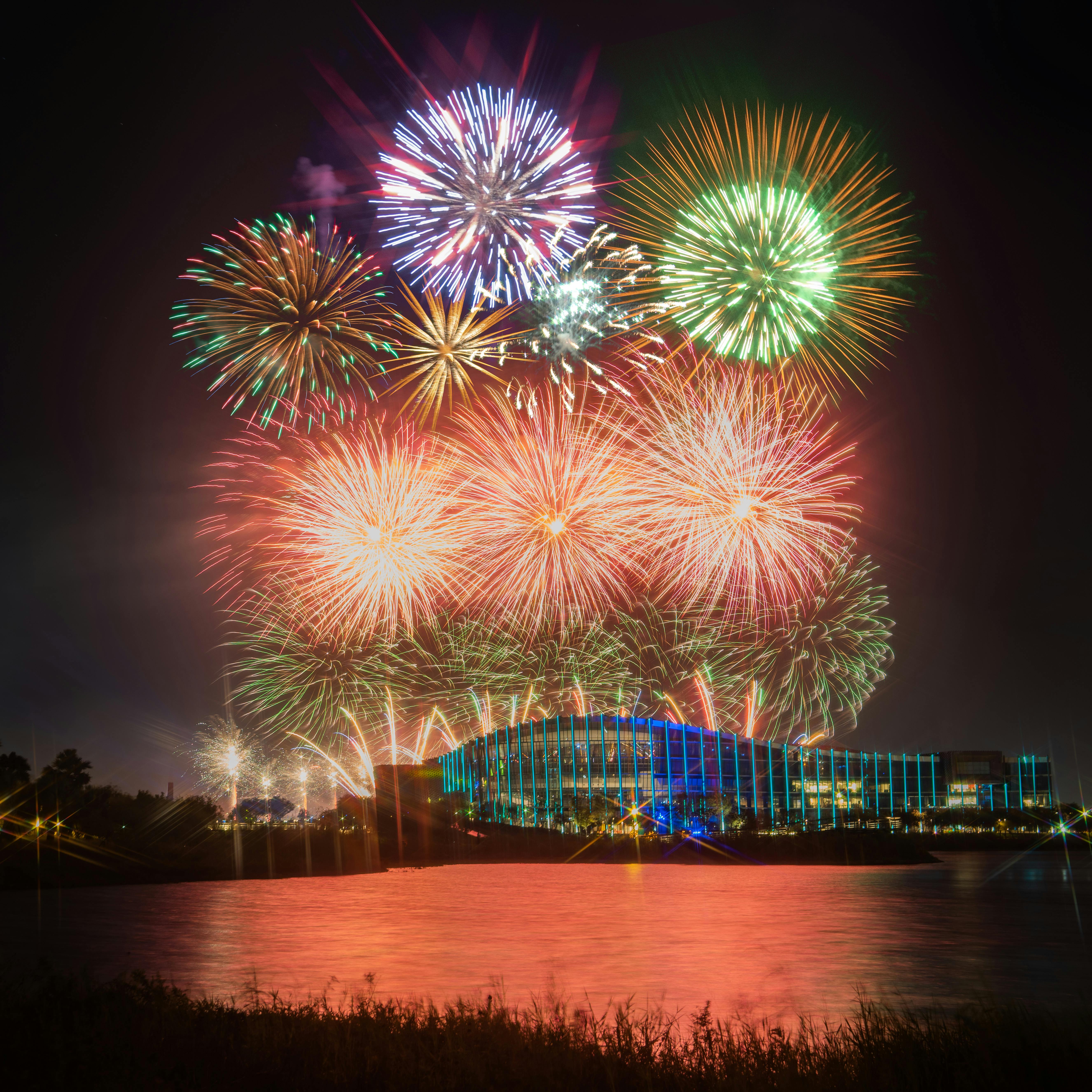 Colorful Fireworks Over a Building Near a Body of Water · Free Stock Photo