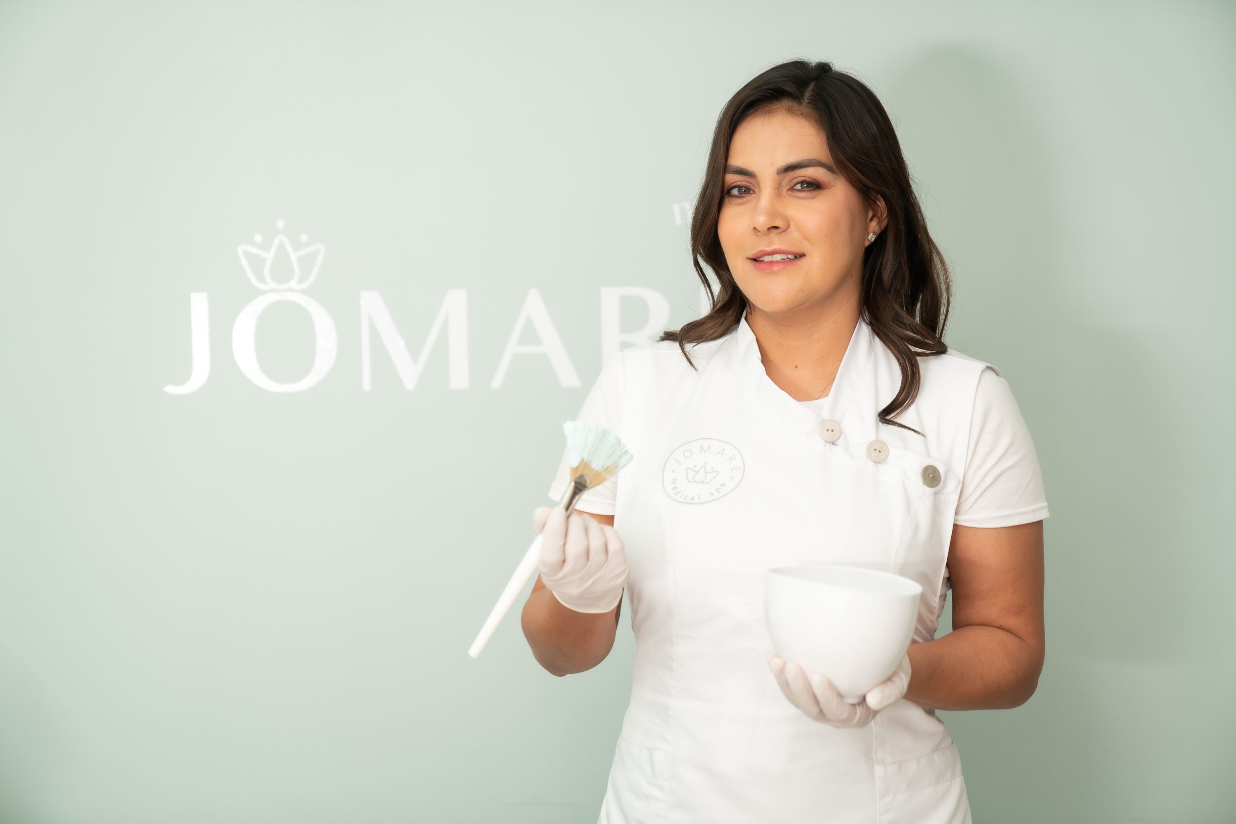 Young Cosmetician in an Apron Holding a Syringe next to Her Cheek ...
