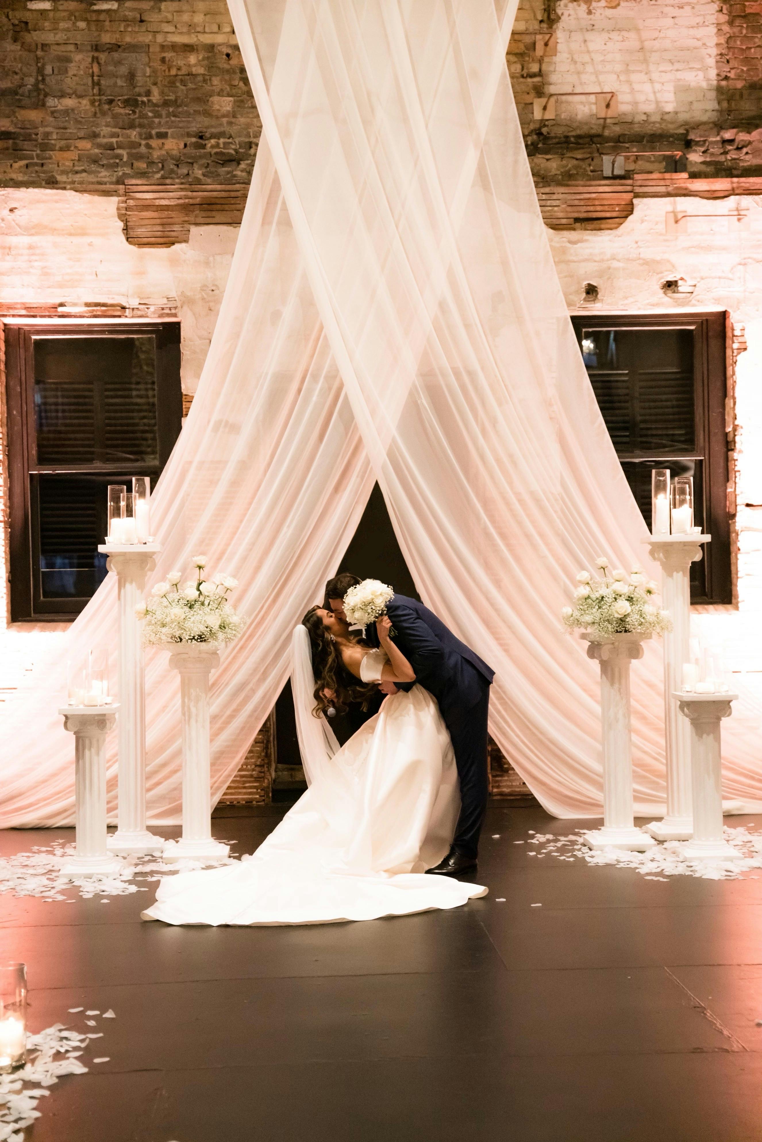 Bride and Groom Sitting on Bench Kissing · Free Stock Photo