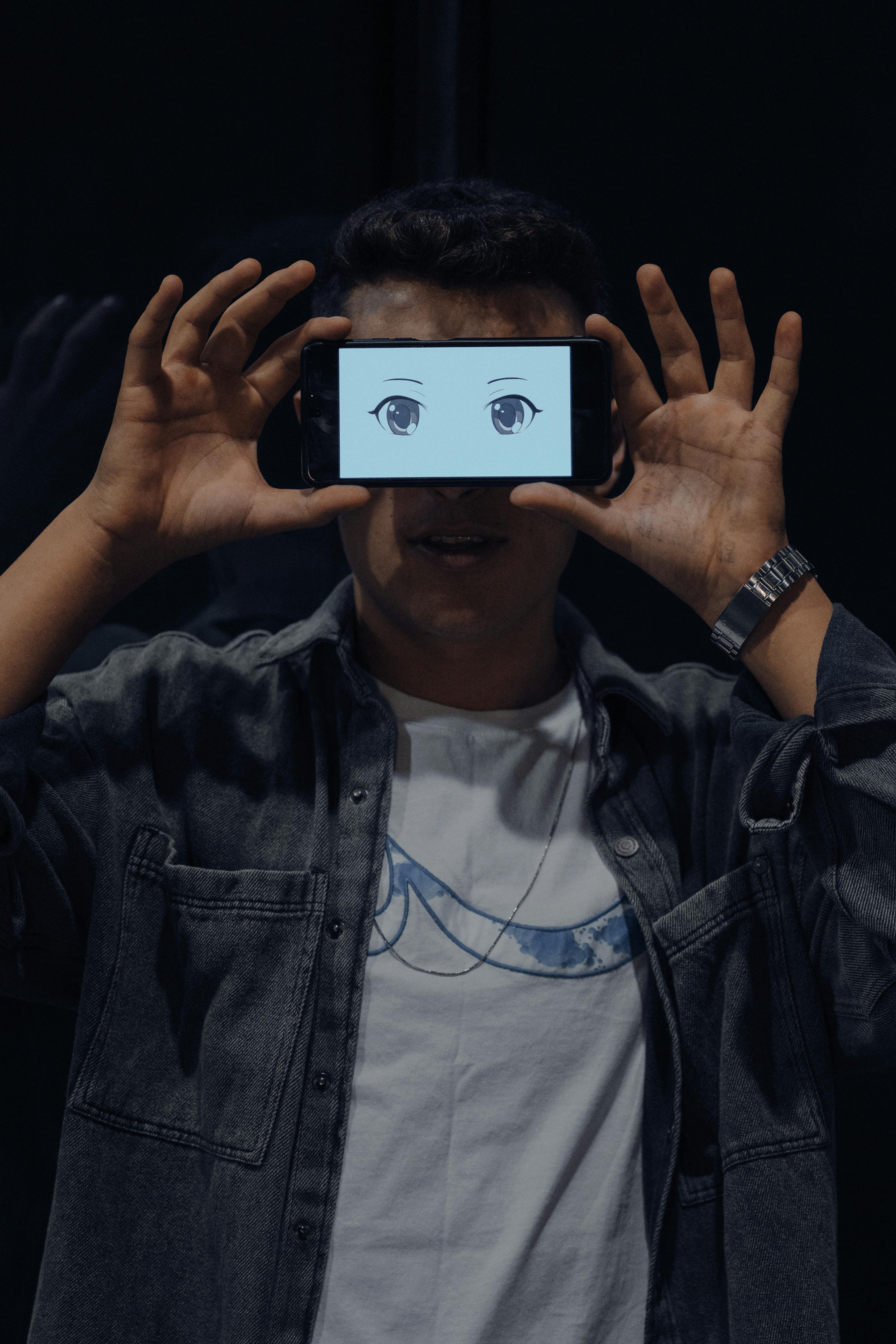 Photo of a Young Man Covering His Face with a Smartphone with His Eyes ...