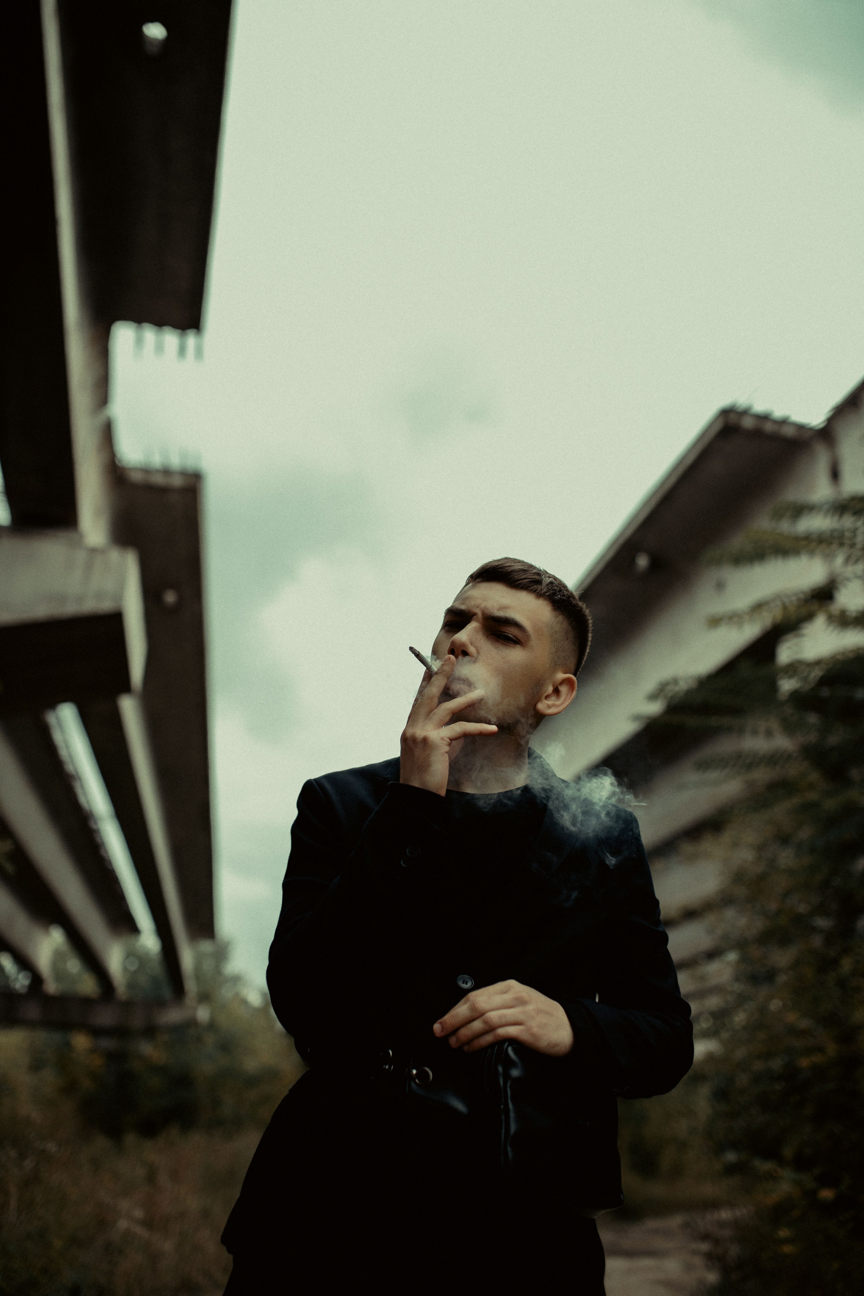 Man in a Peaked Cap Standing Outside at Sunset and Smoking a Cigarette ...
