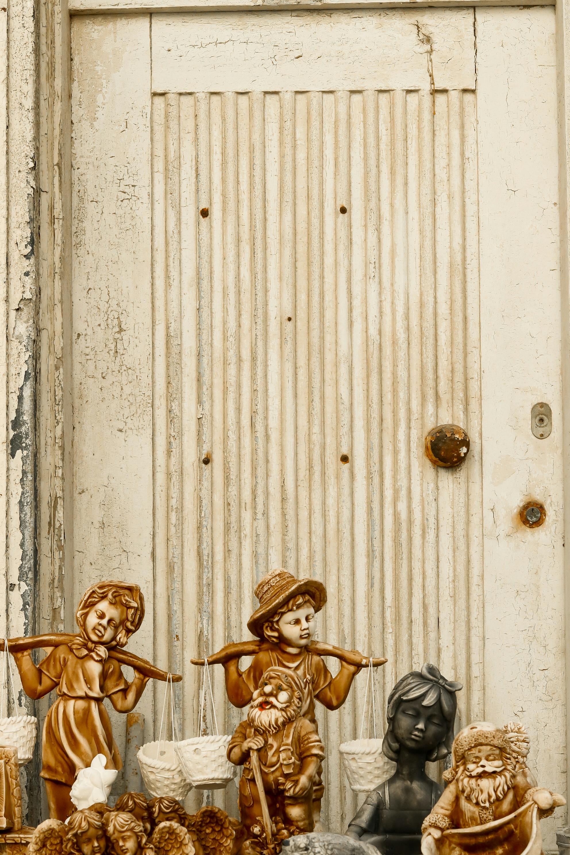 Figurines in front of Old Door · Free Stock Photo