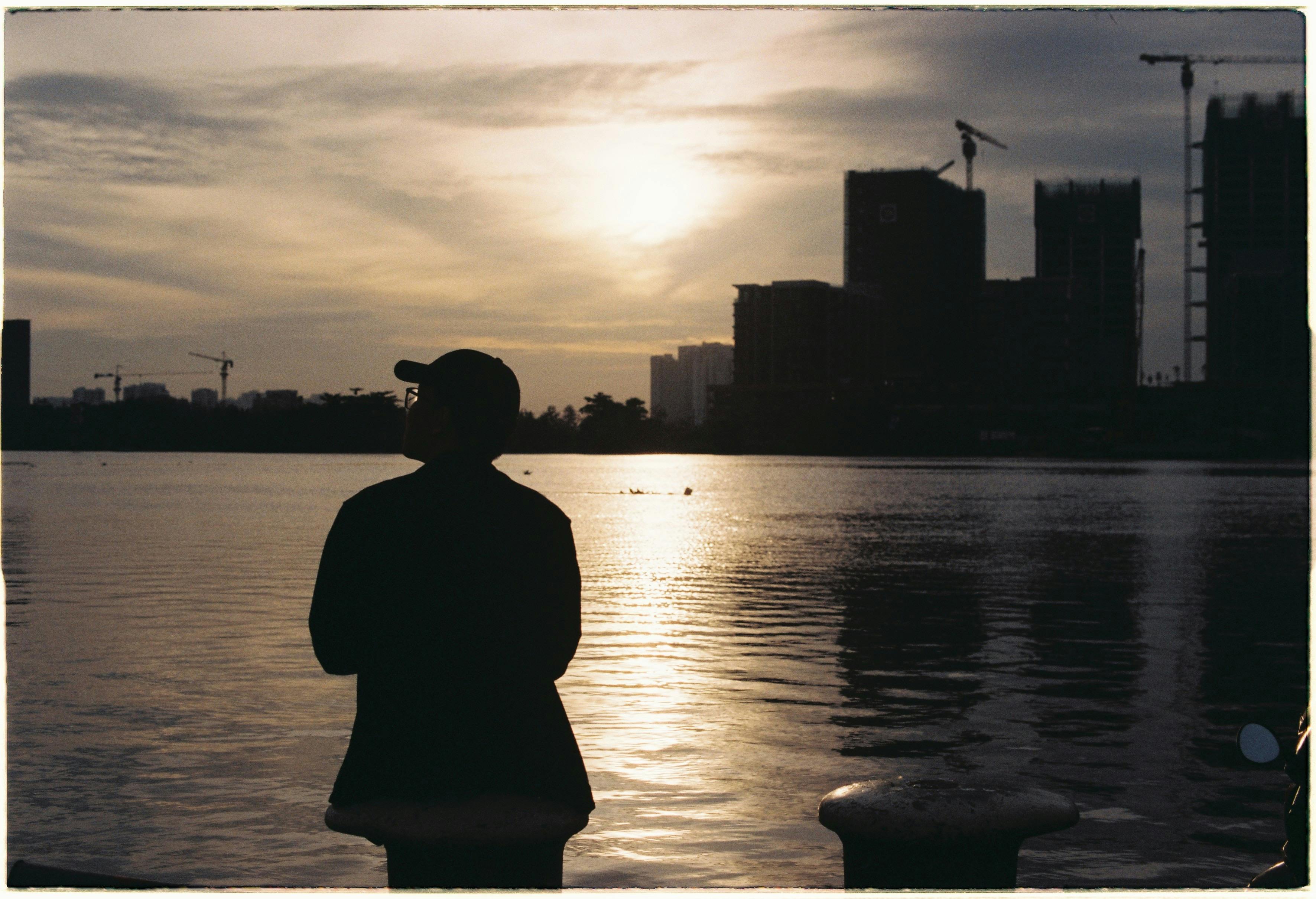 Silhouette of Man Standing Near Body of Water during Sunset · Free ...