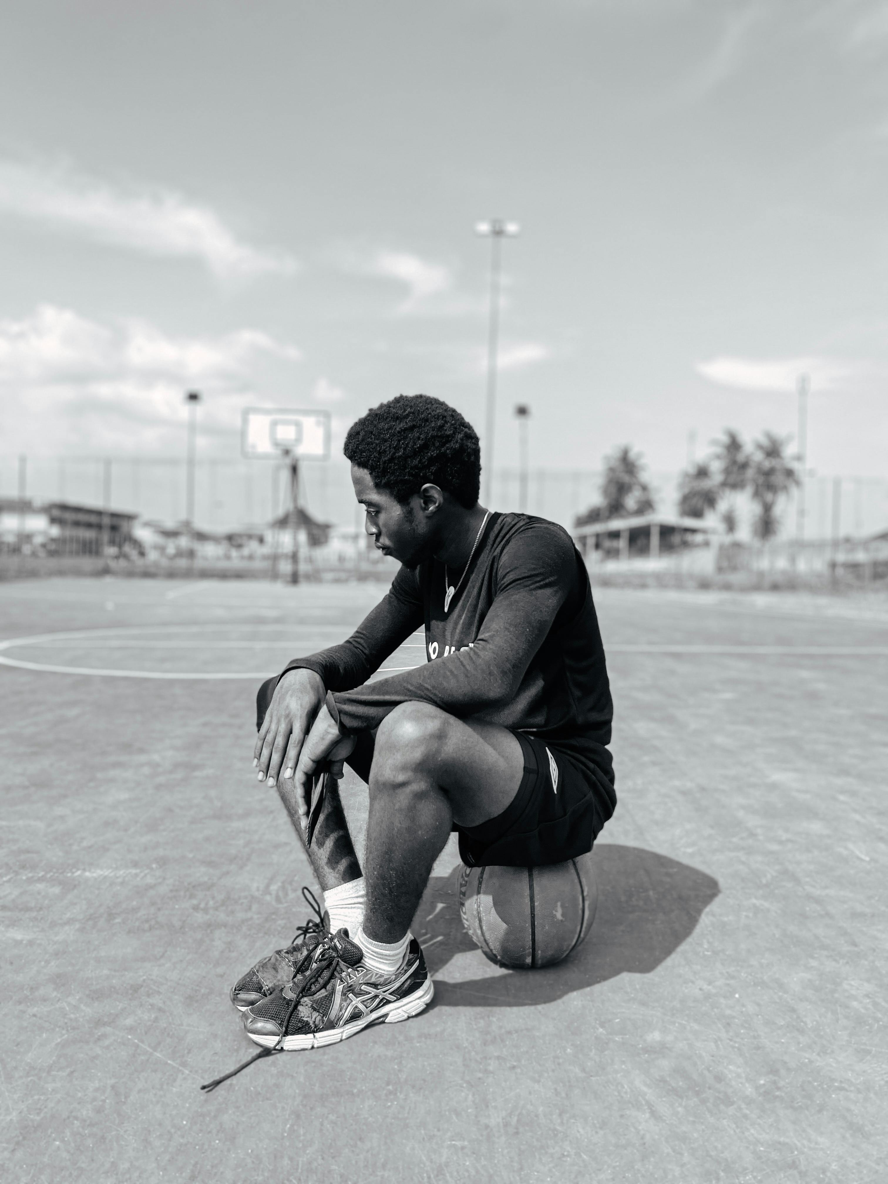 Grayscale Photo of Man Sitting Ball · Free Stock Photo