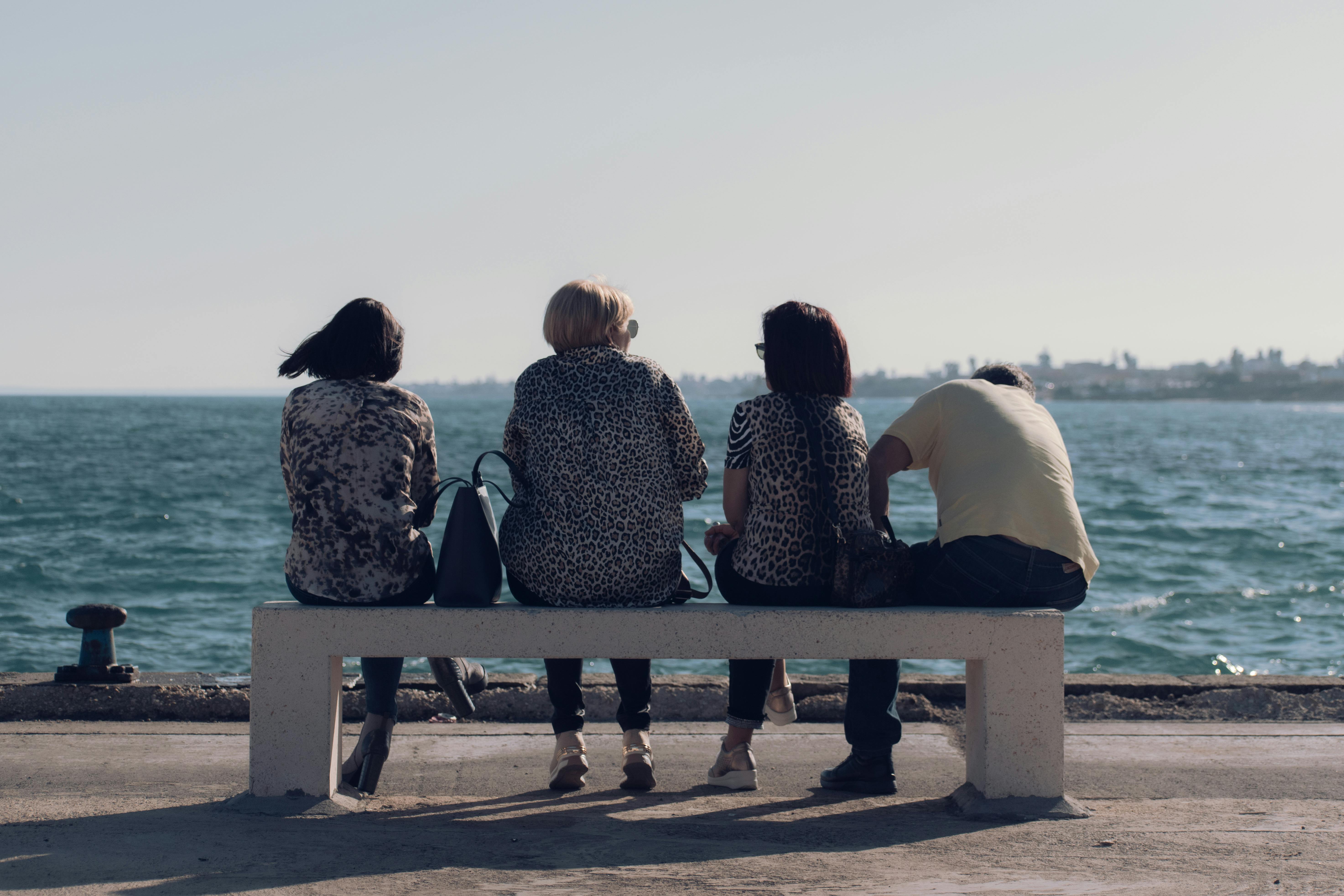 People Sitting on Concrete Bench near Body of Water · Free Stock Photo