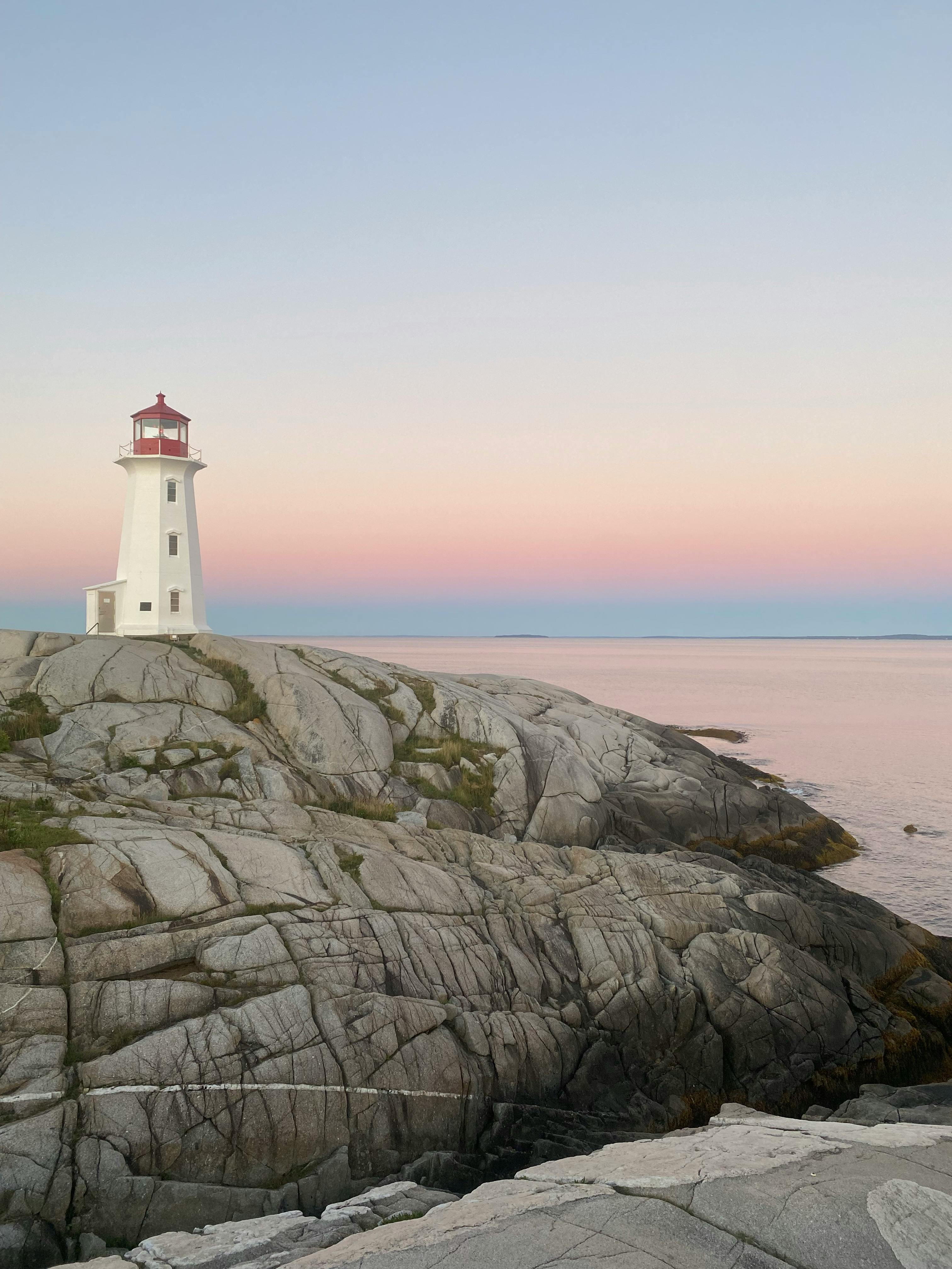 White and Red Lighthouse on Brown Rock Formation Near Body of Water ...