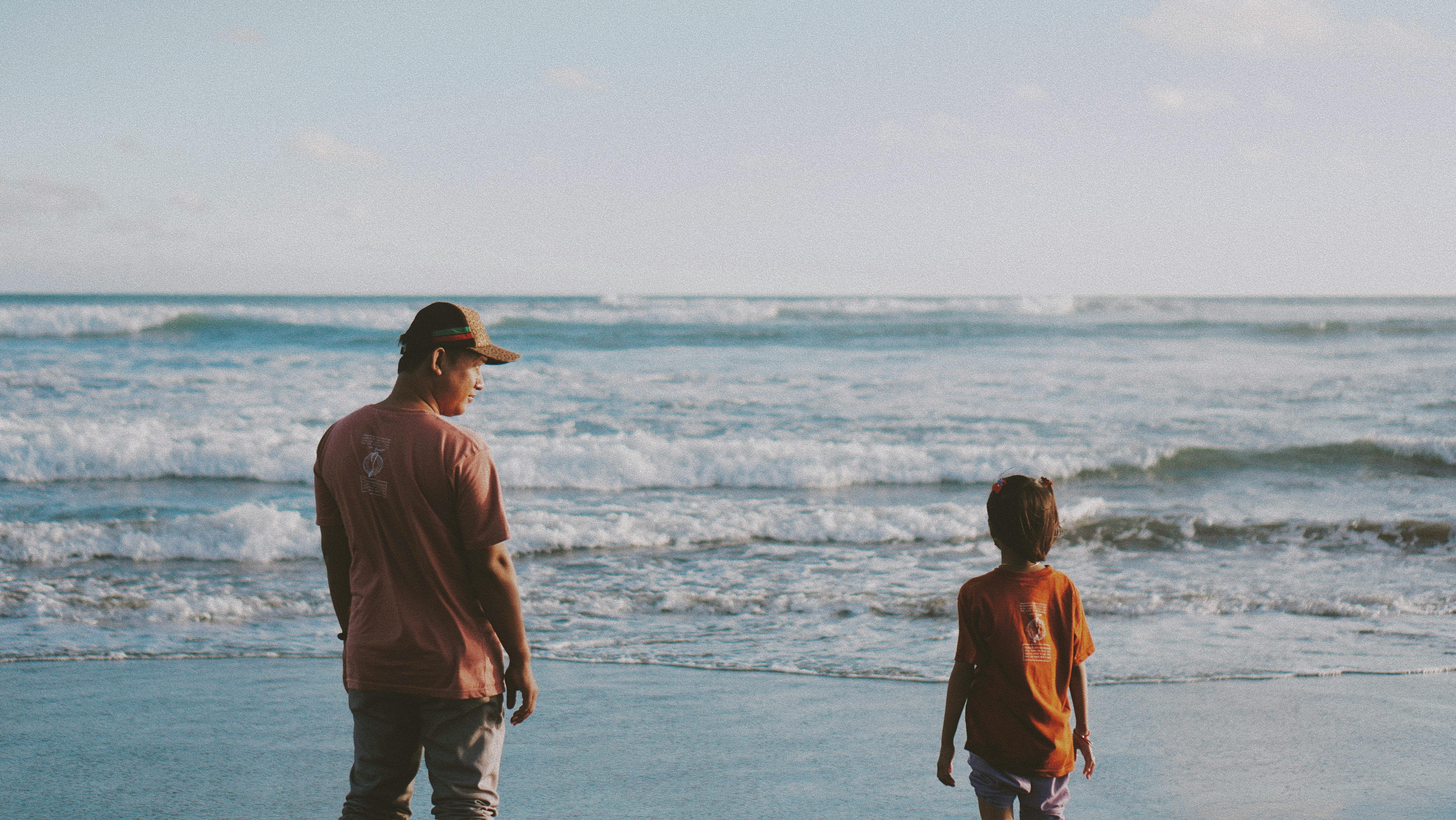 Man and Child Standing on Beach · Free Stock Photo