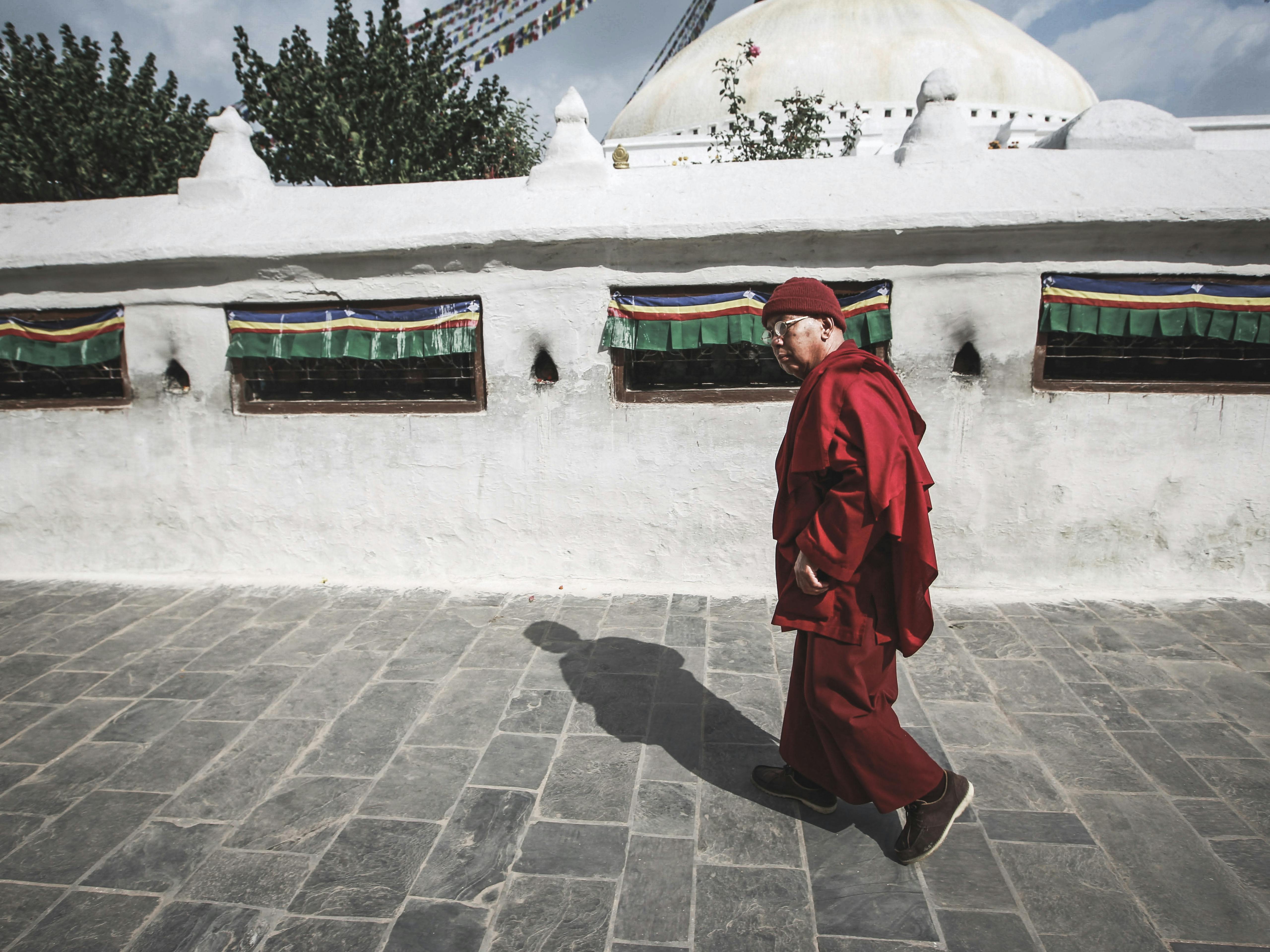 Man in Red Thobe Walking Near Concrete Structure · Free Stock Photo