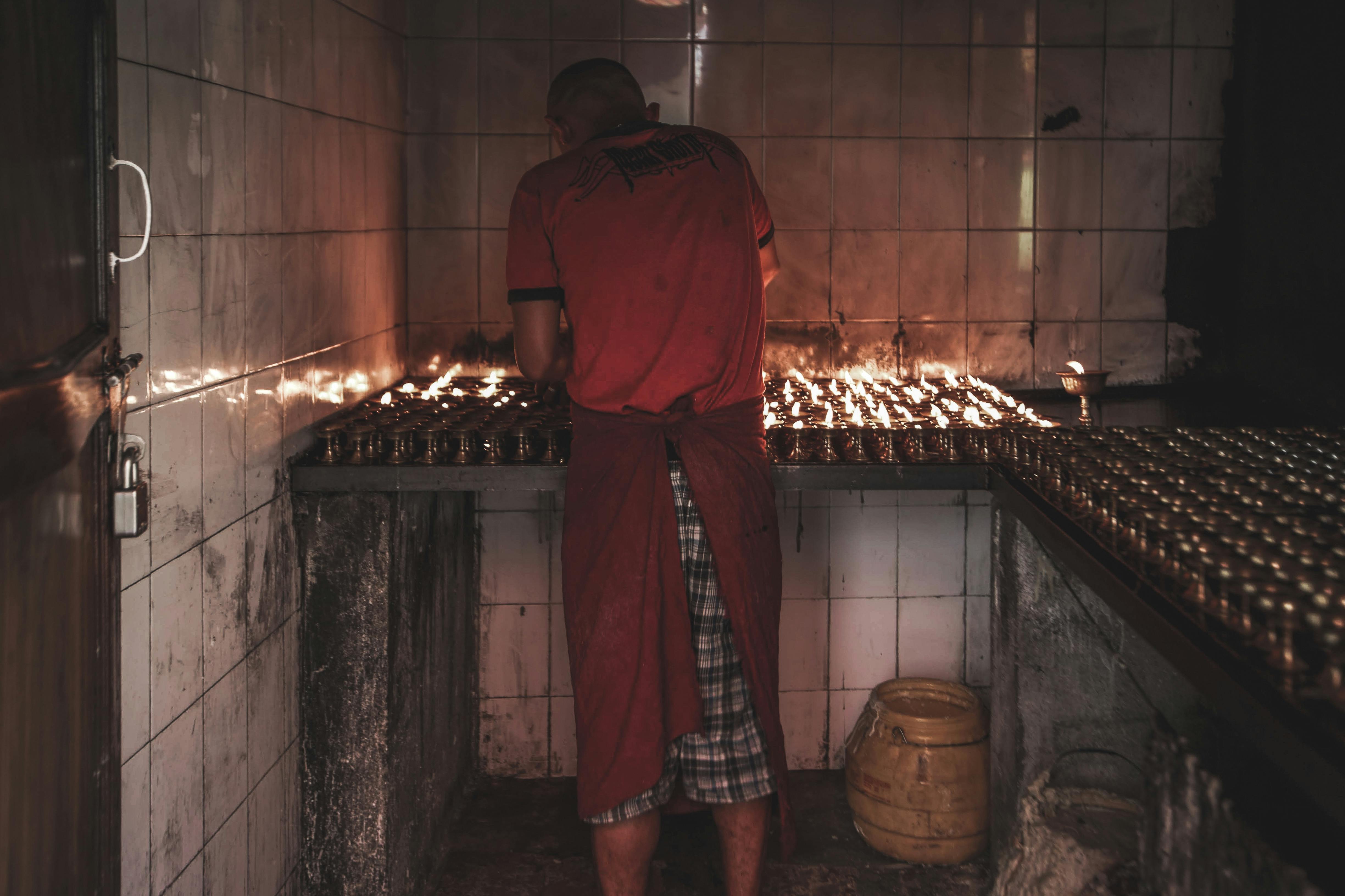 Back View of a Man Lighting Candles · Free Stock Photo