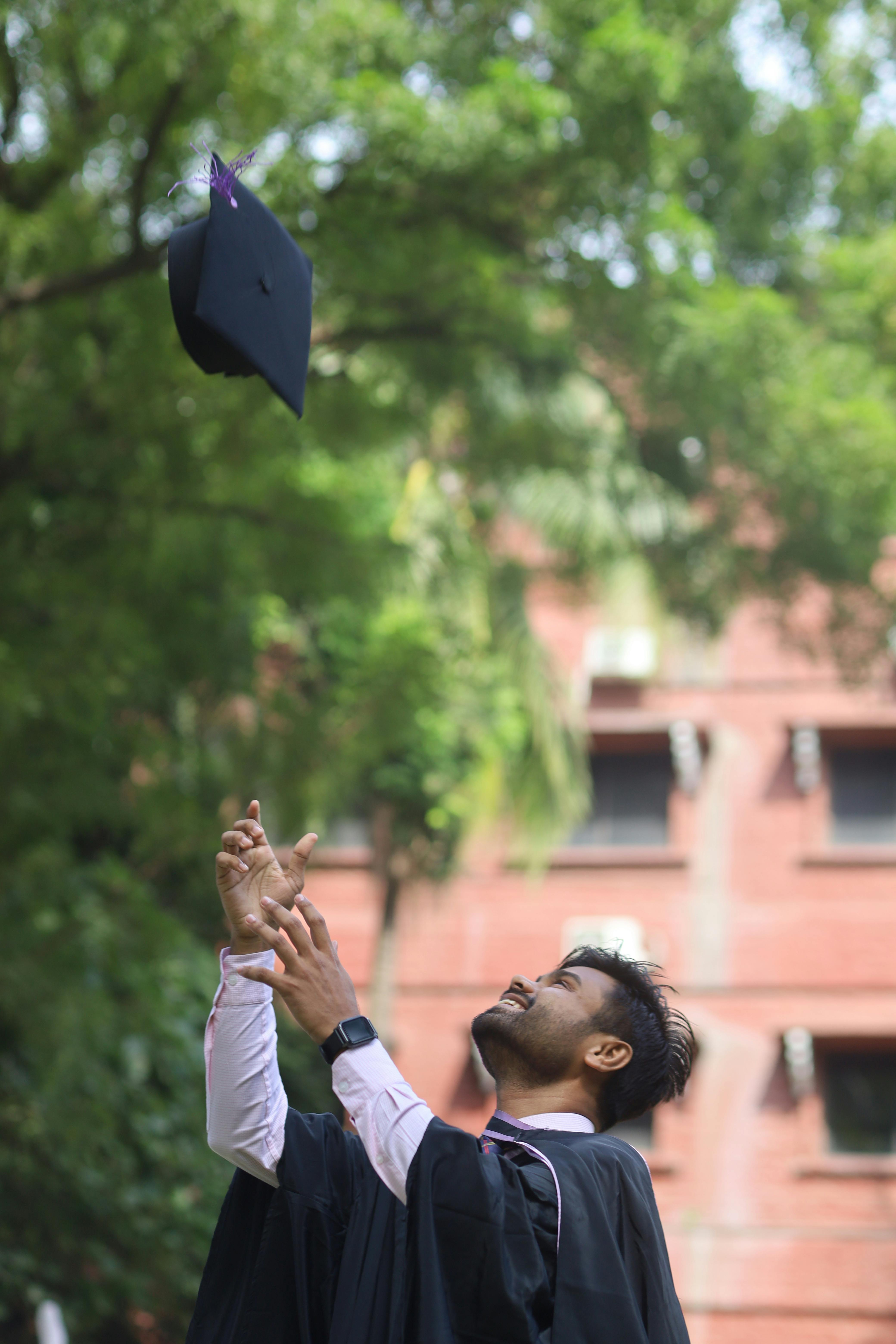 A Man in Black Graduation Gown Throwing the Black Graduation Cap · Free ...