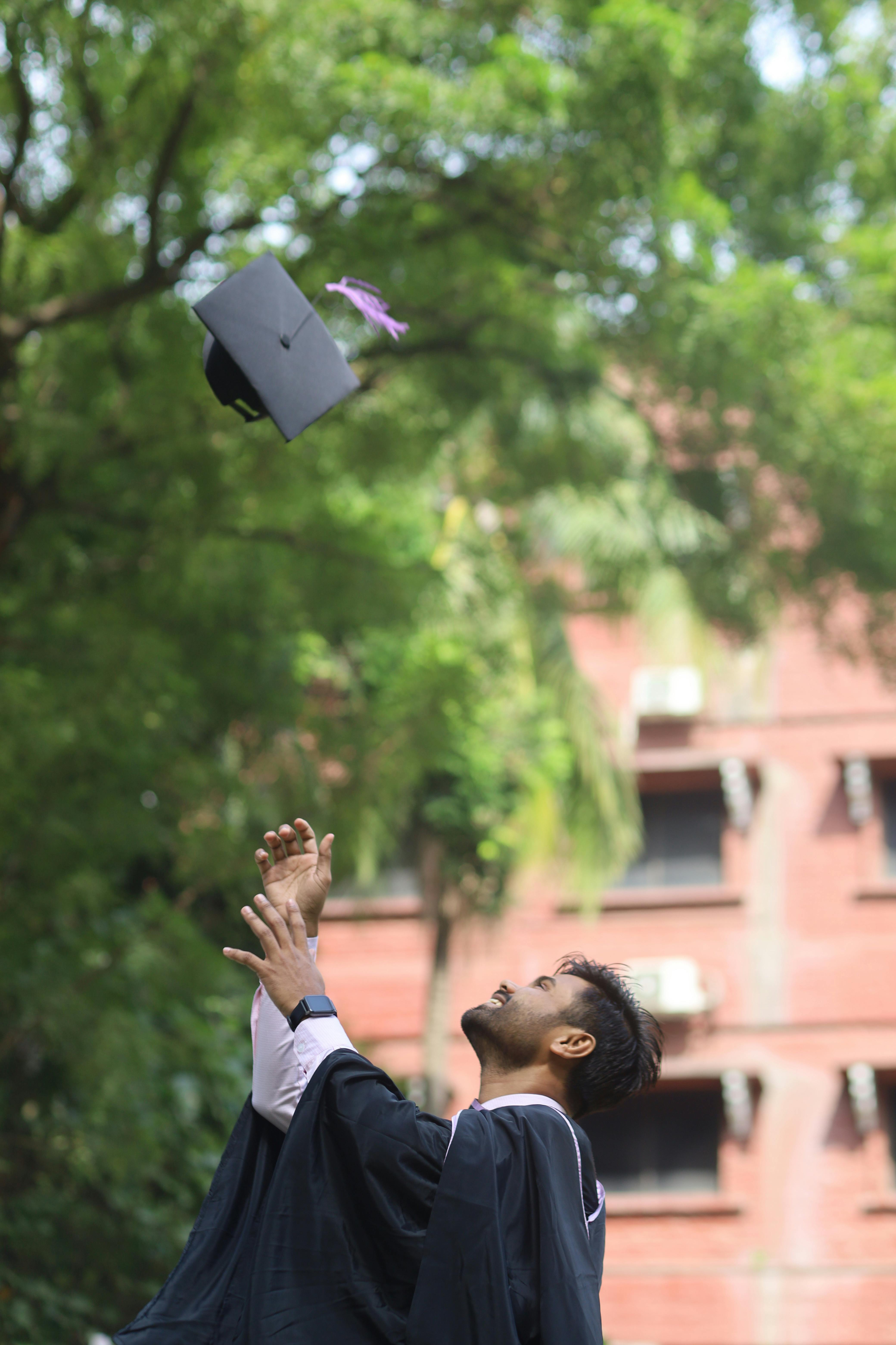 University Student in Graduation Gown Holding a Diploma · Free Stock Photo