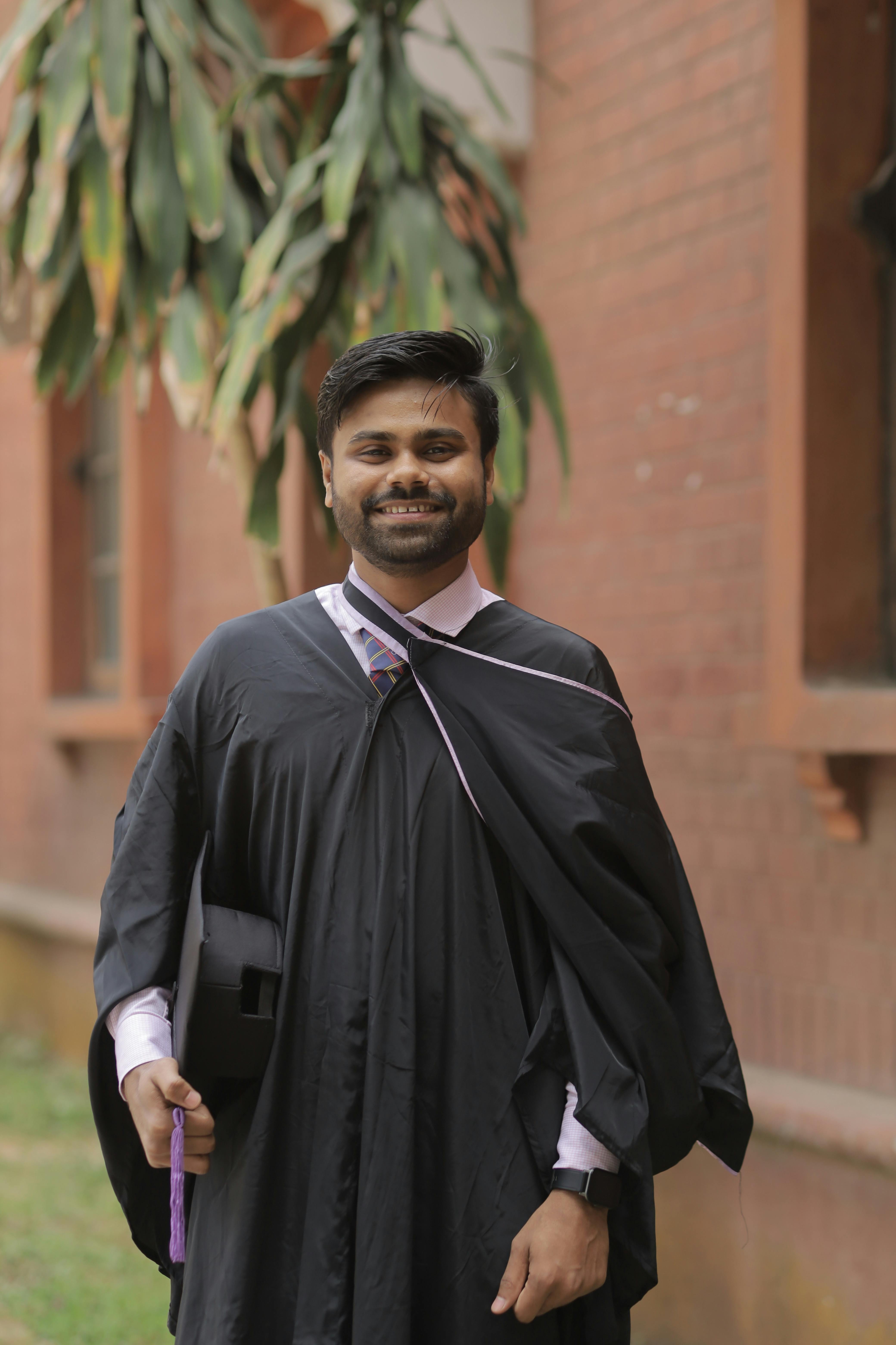 A Man in Black Academic Dress Standing Near Brick Building while ...
