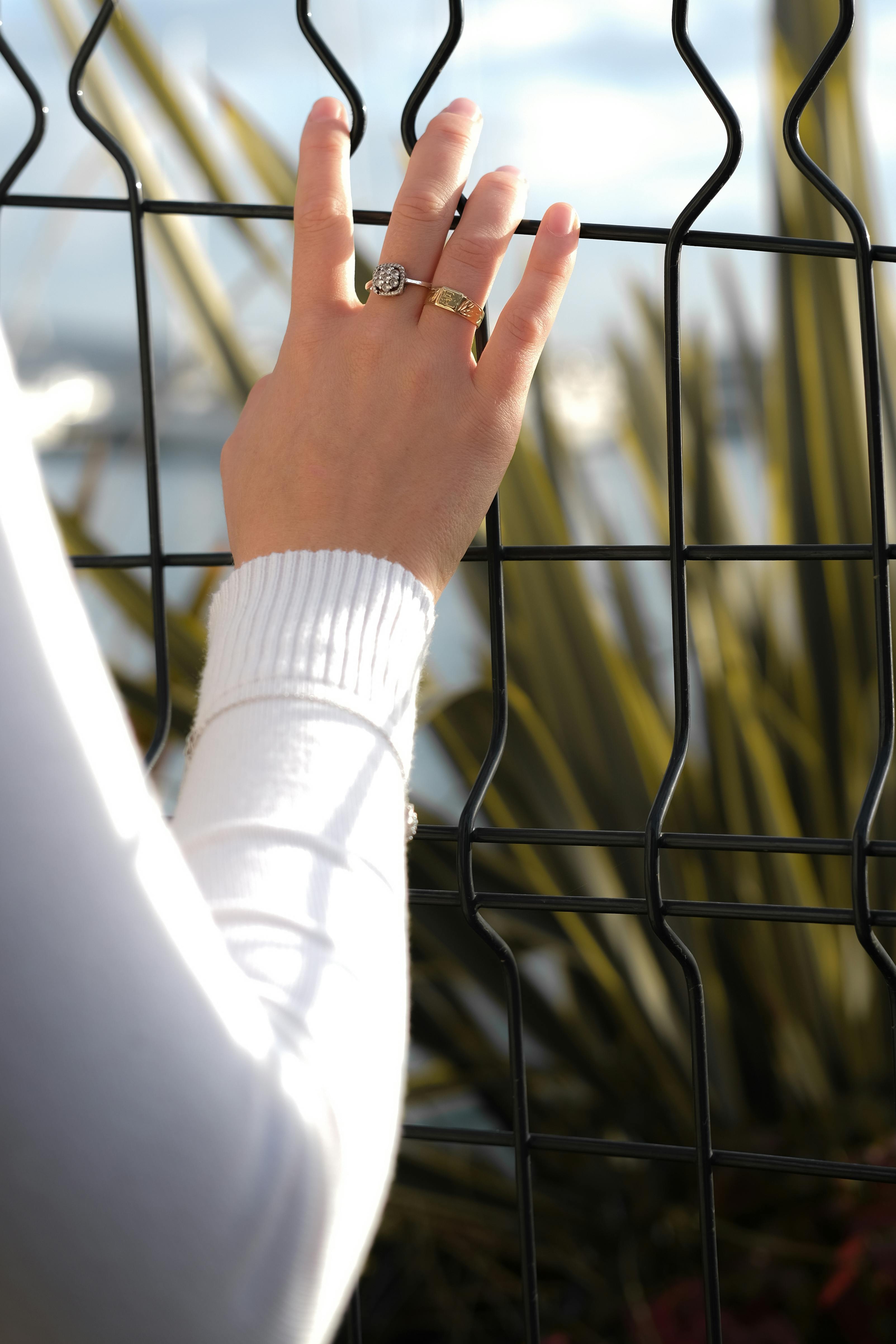 Person Wearing Gold Rings Holding on Fence · Free Stock Photo
