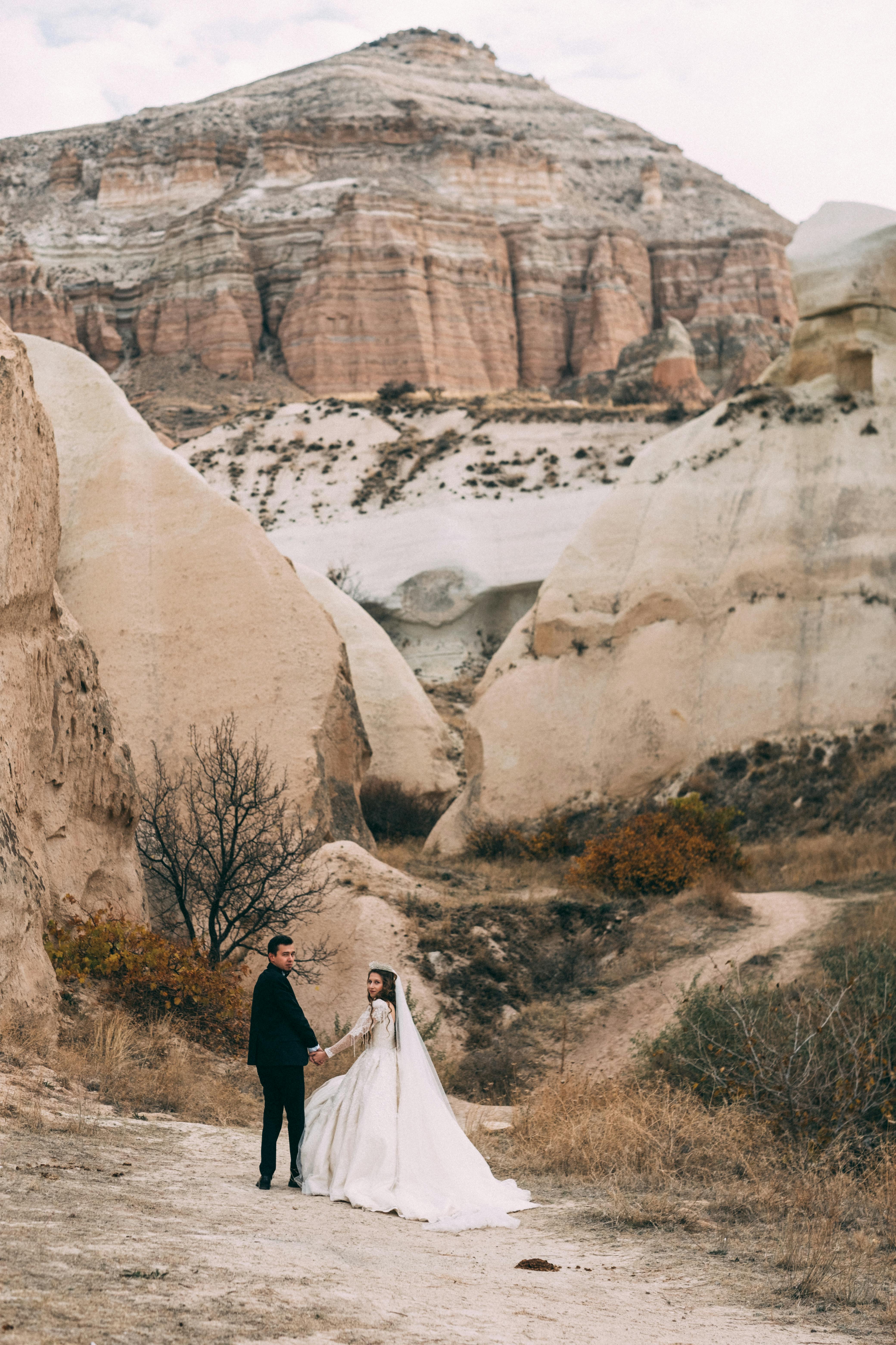 Newlyweds Standing Together on Dirt Road near Rock Formations · Free ...