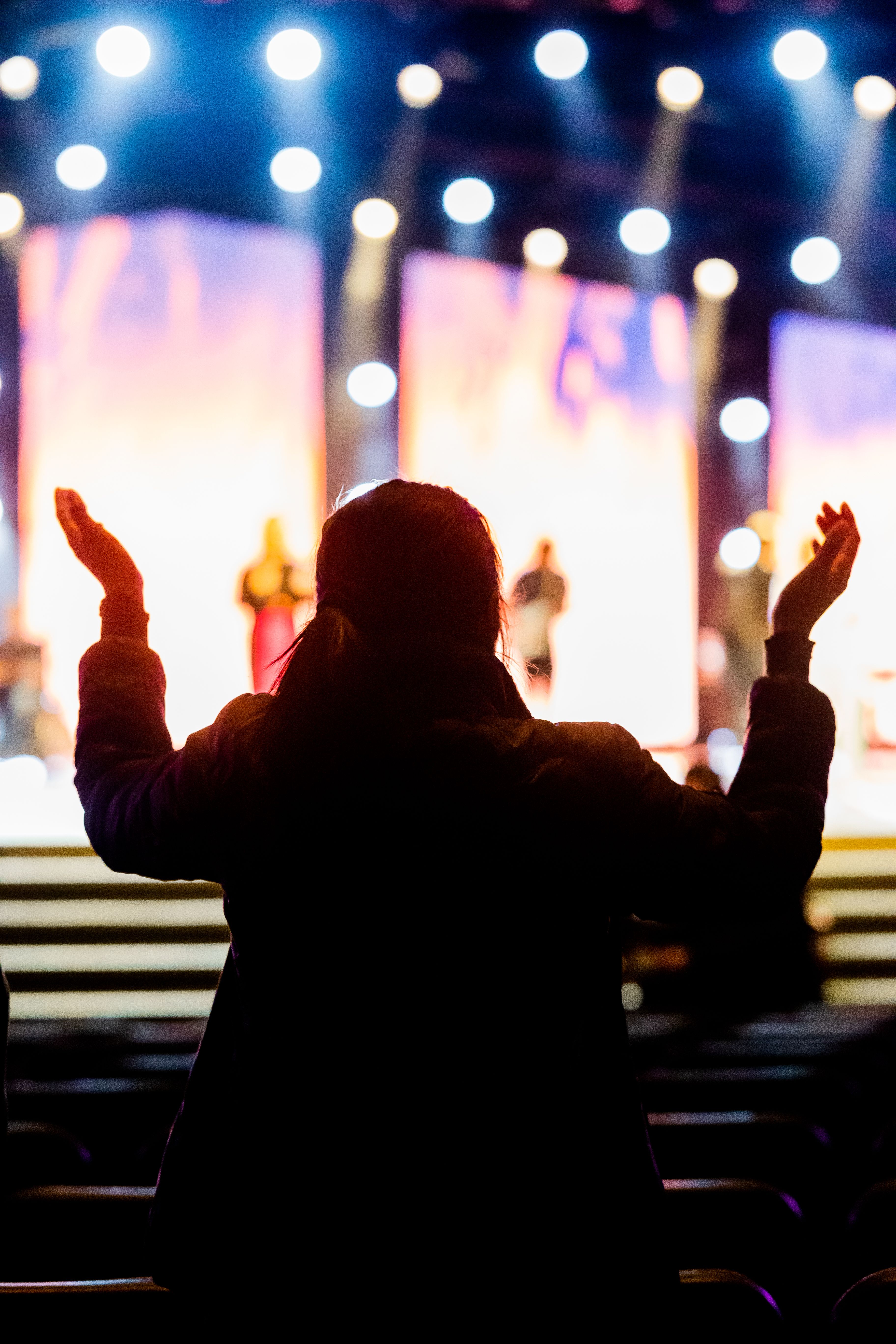 Person in Black Jacket Standing with Arms Raised · Free Stock Photo