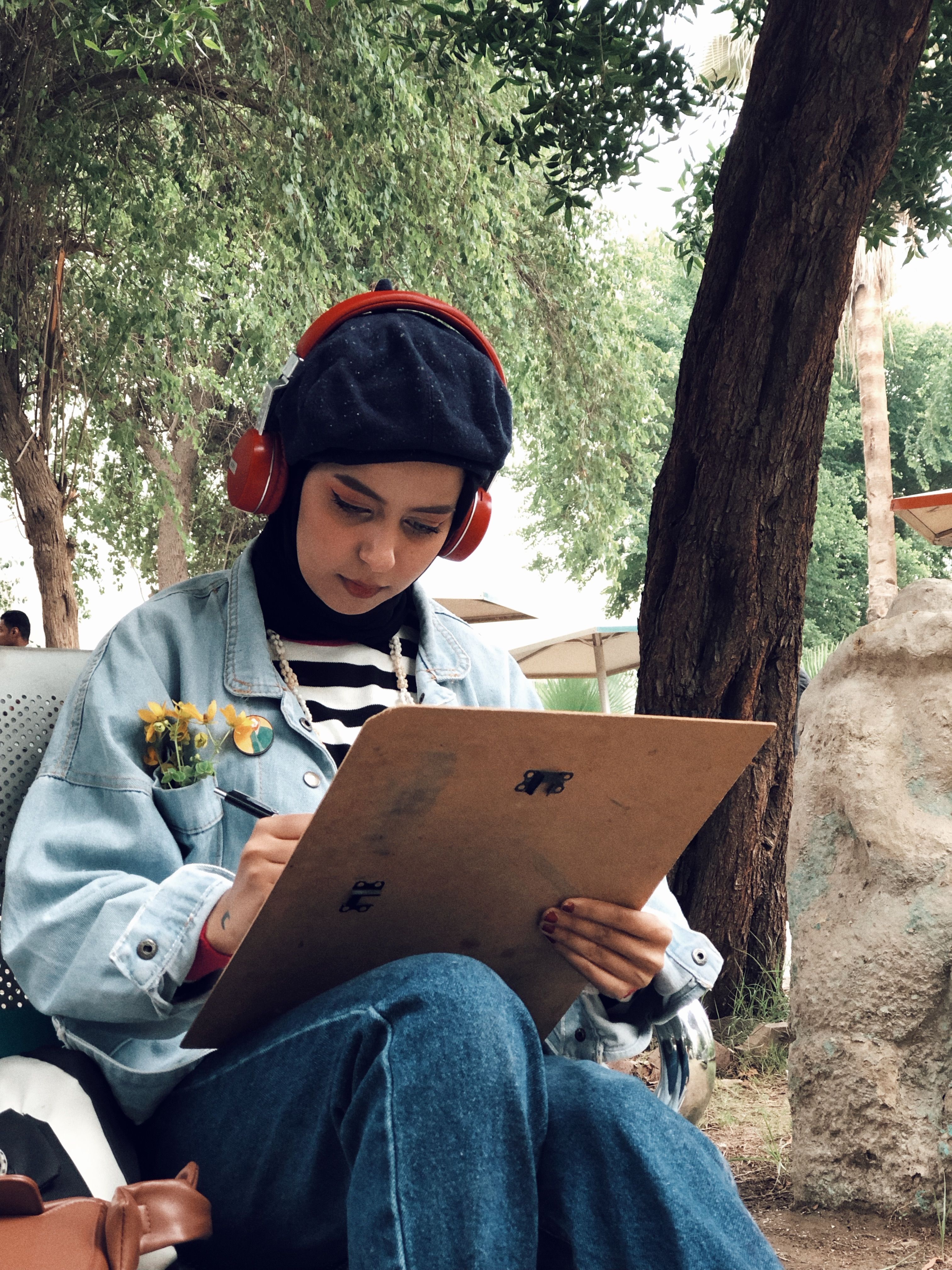 Woman in Denim Jacket Writing While Holding a Clipboard · Free Stock Photo