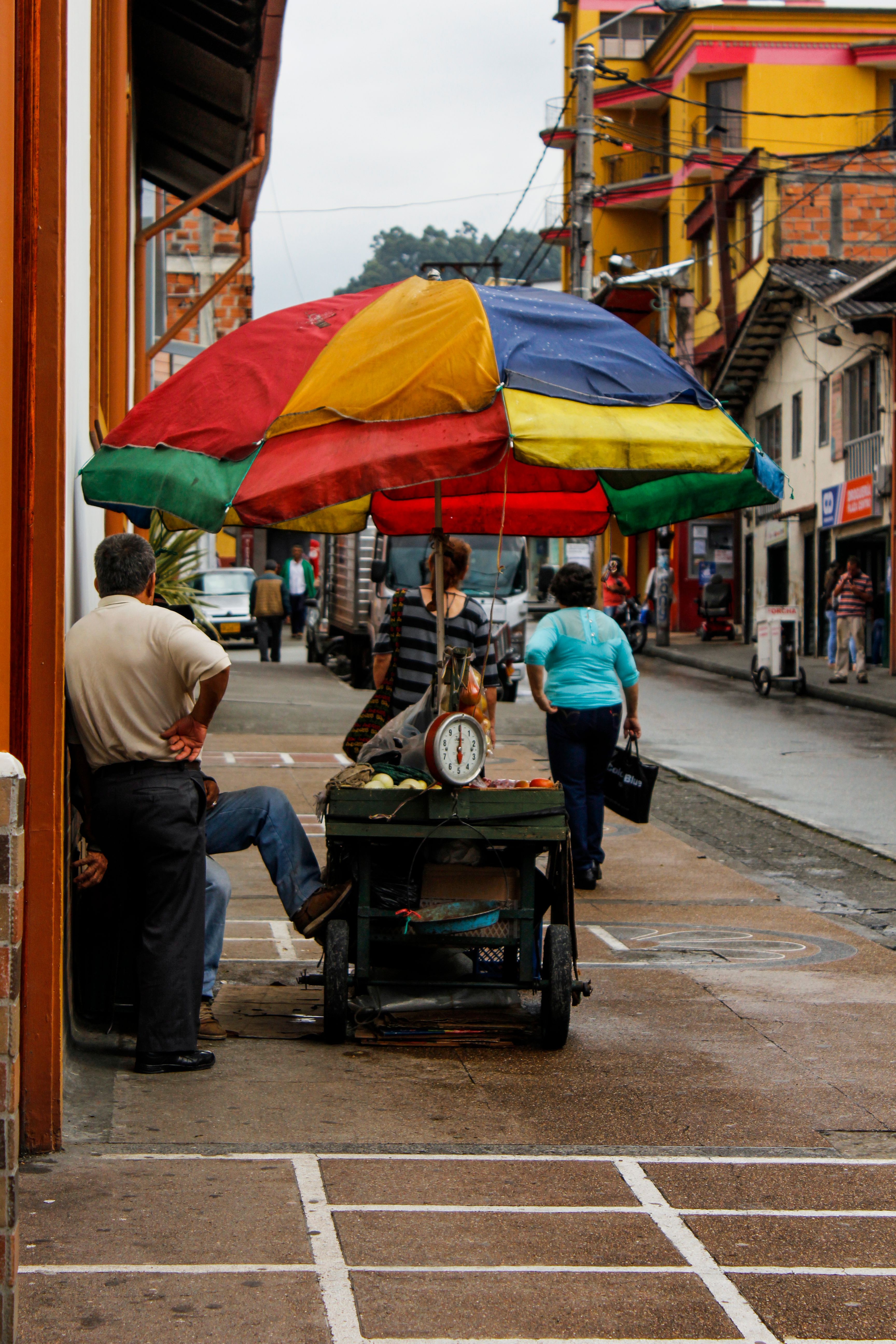 Street Vendor With Colorful Umbrella Near Sidewalk · Free Stock Photo