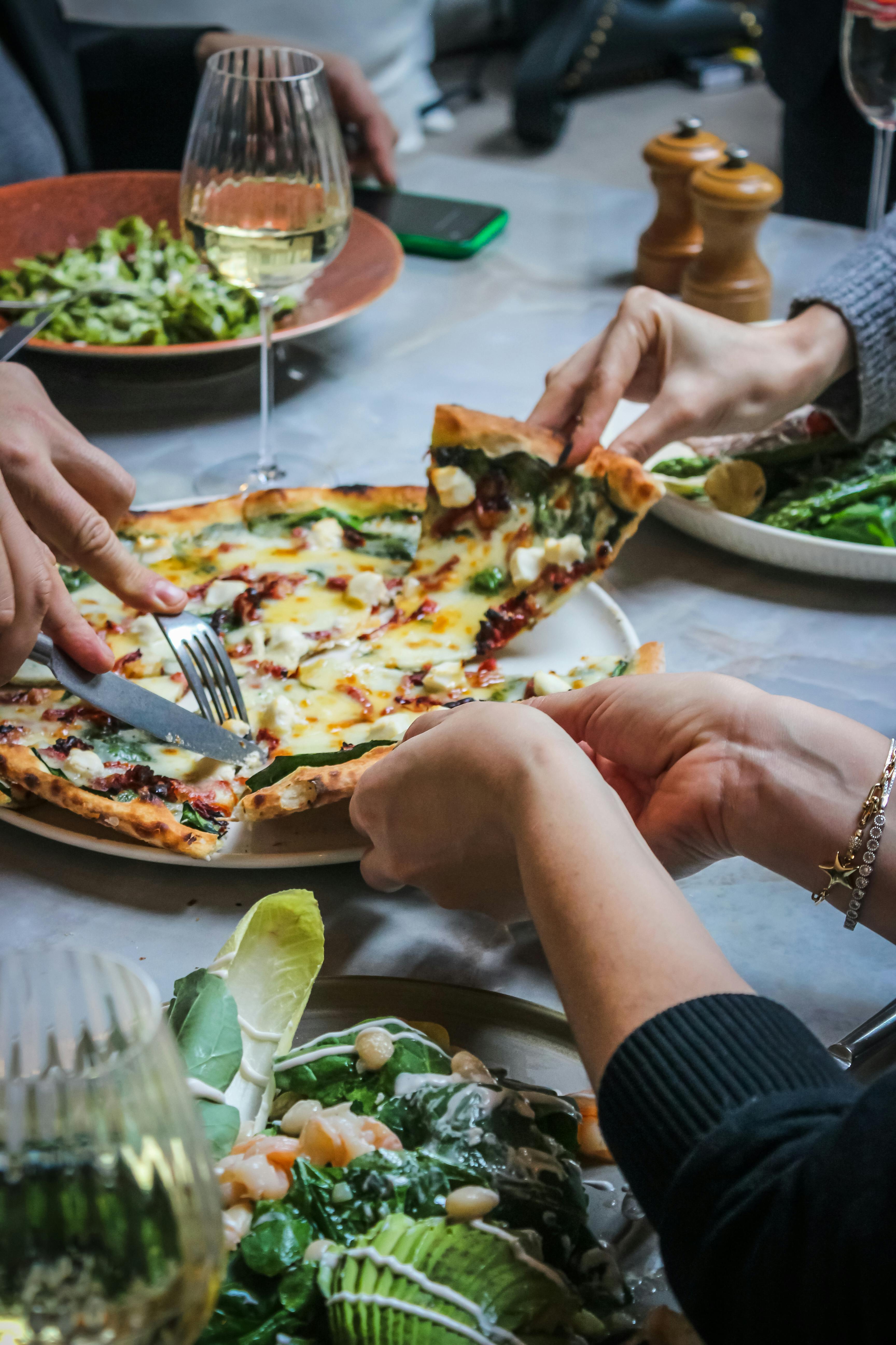 Hands around Pizza on Table · Free Stock Photo
