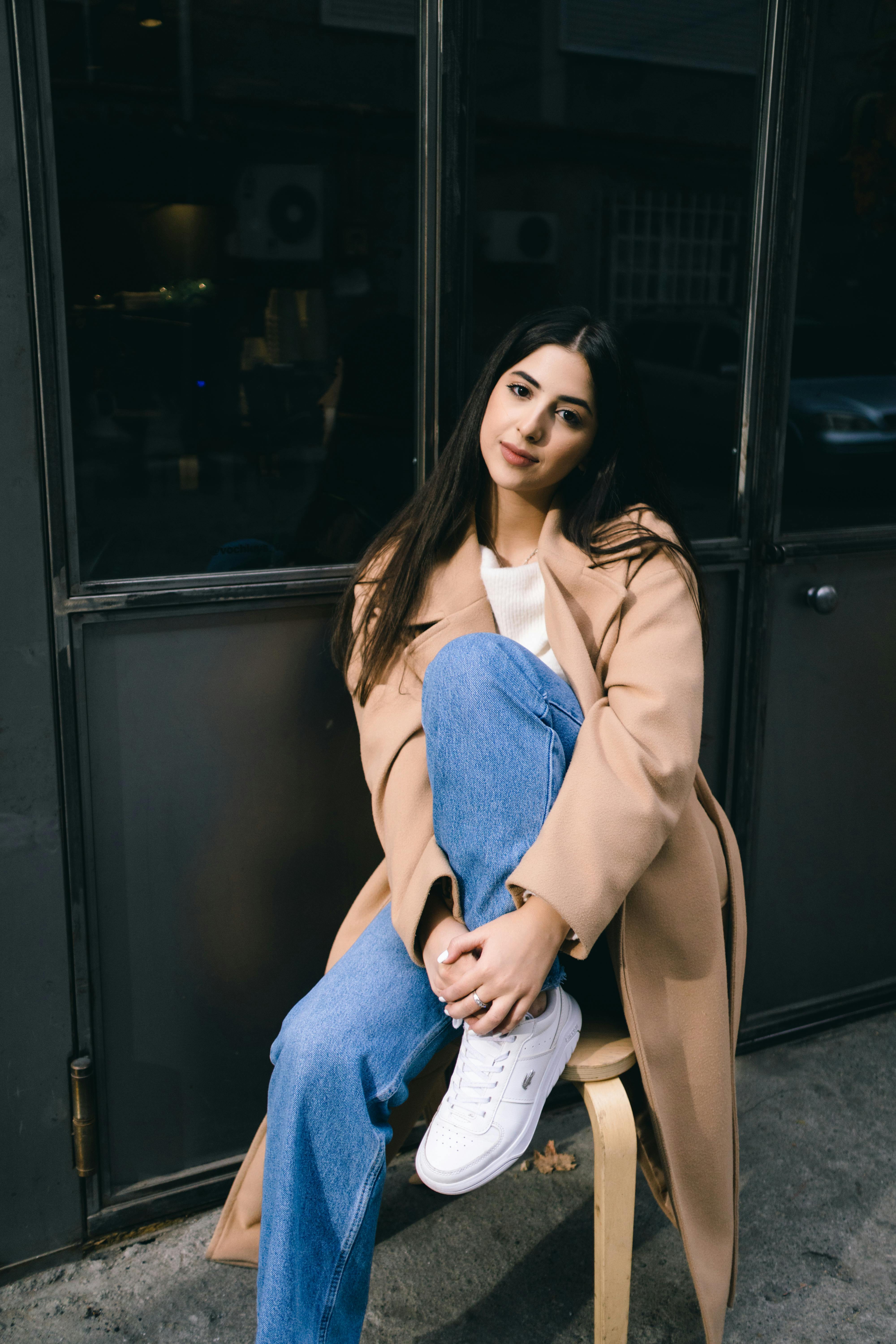 Beautiful Woman in Brown Coat and Denim Jeans Posing · Free Stock Photo