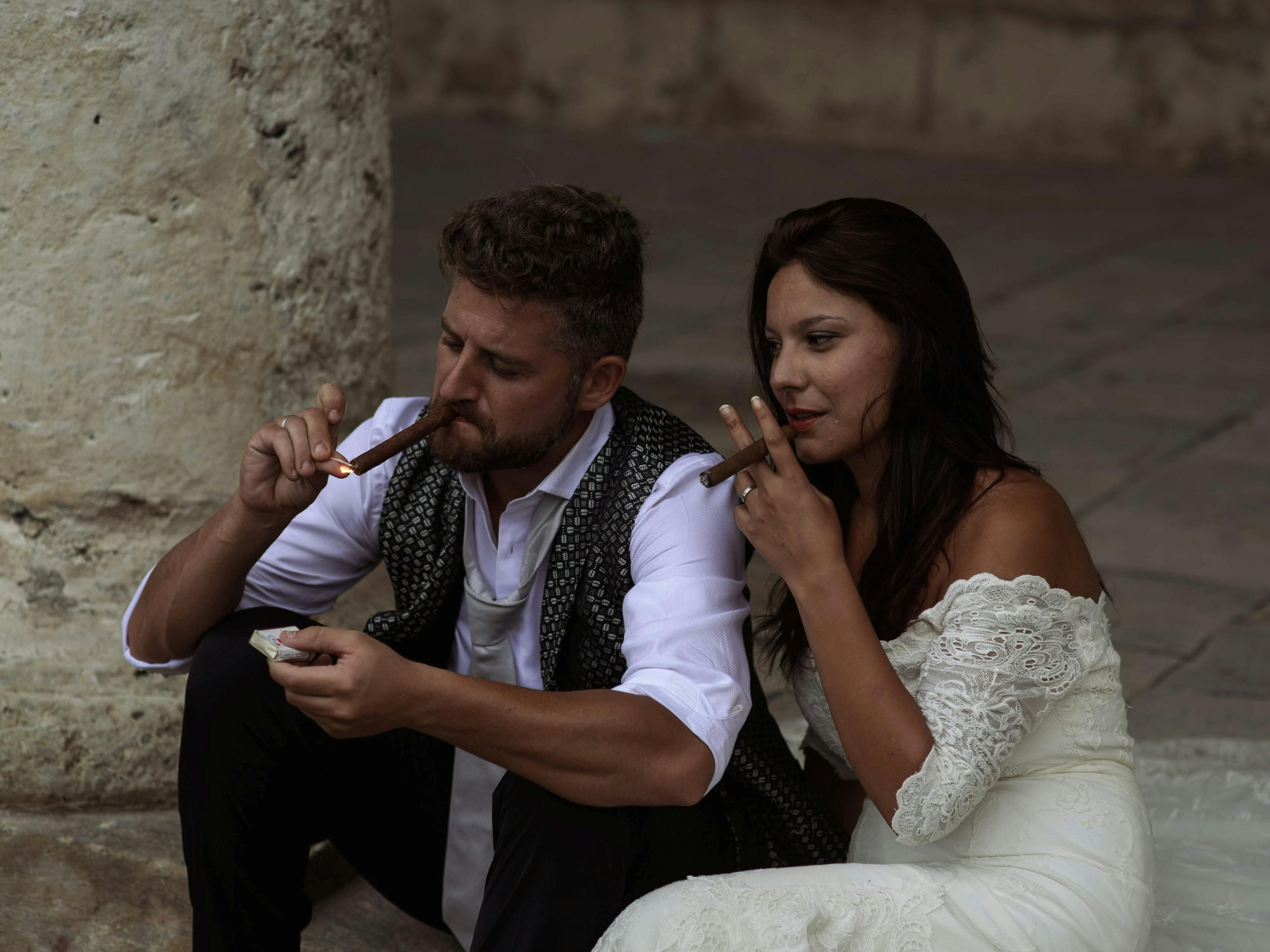 Bride and Groom Smoking Cigars Outdoors · Free Stock Photo