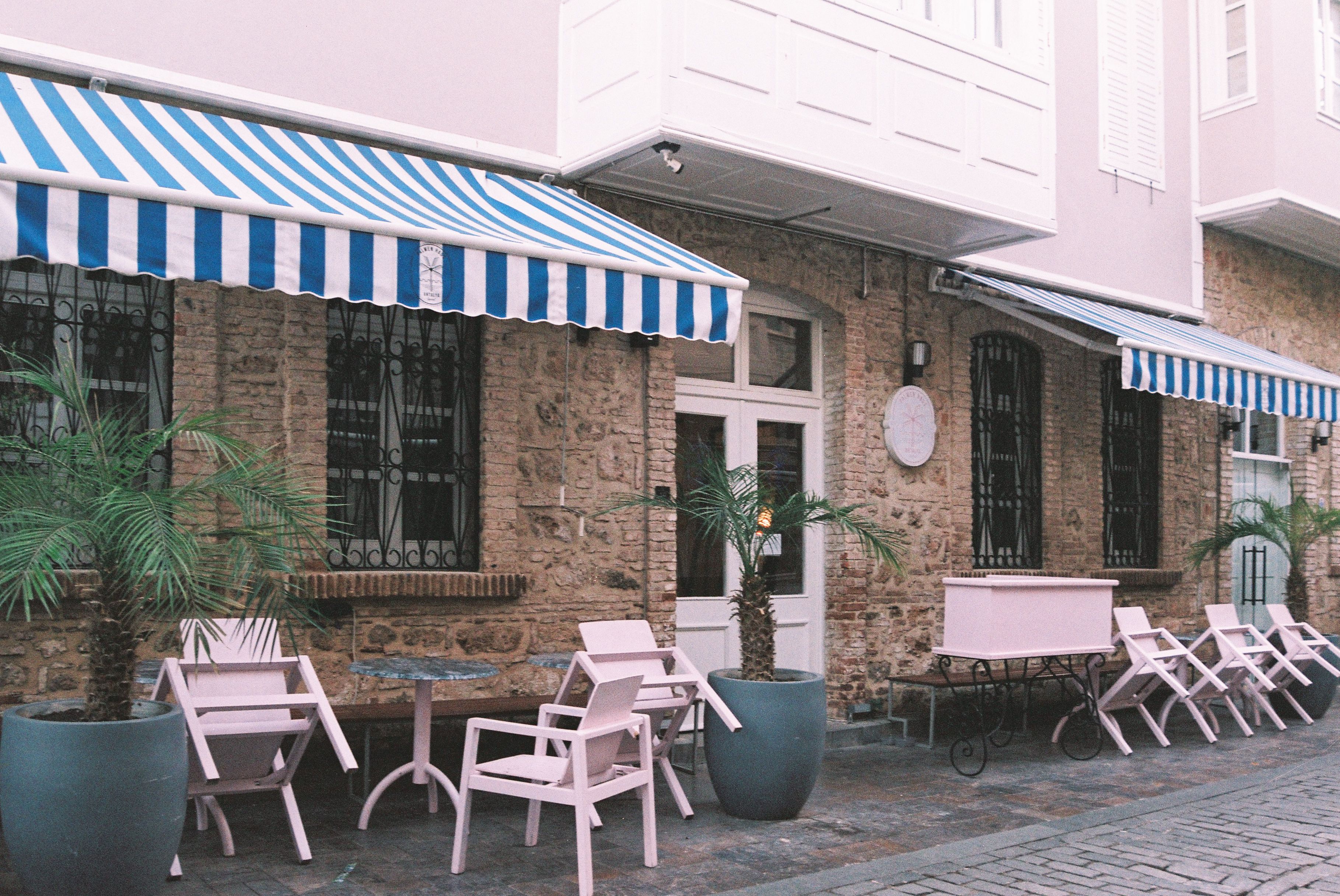 Brick Building Facade with Striped Sunshades and White Garden Furniture ...