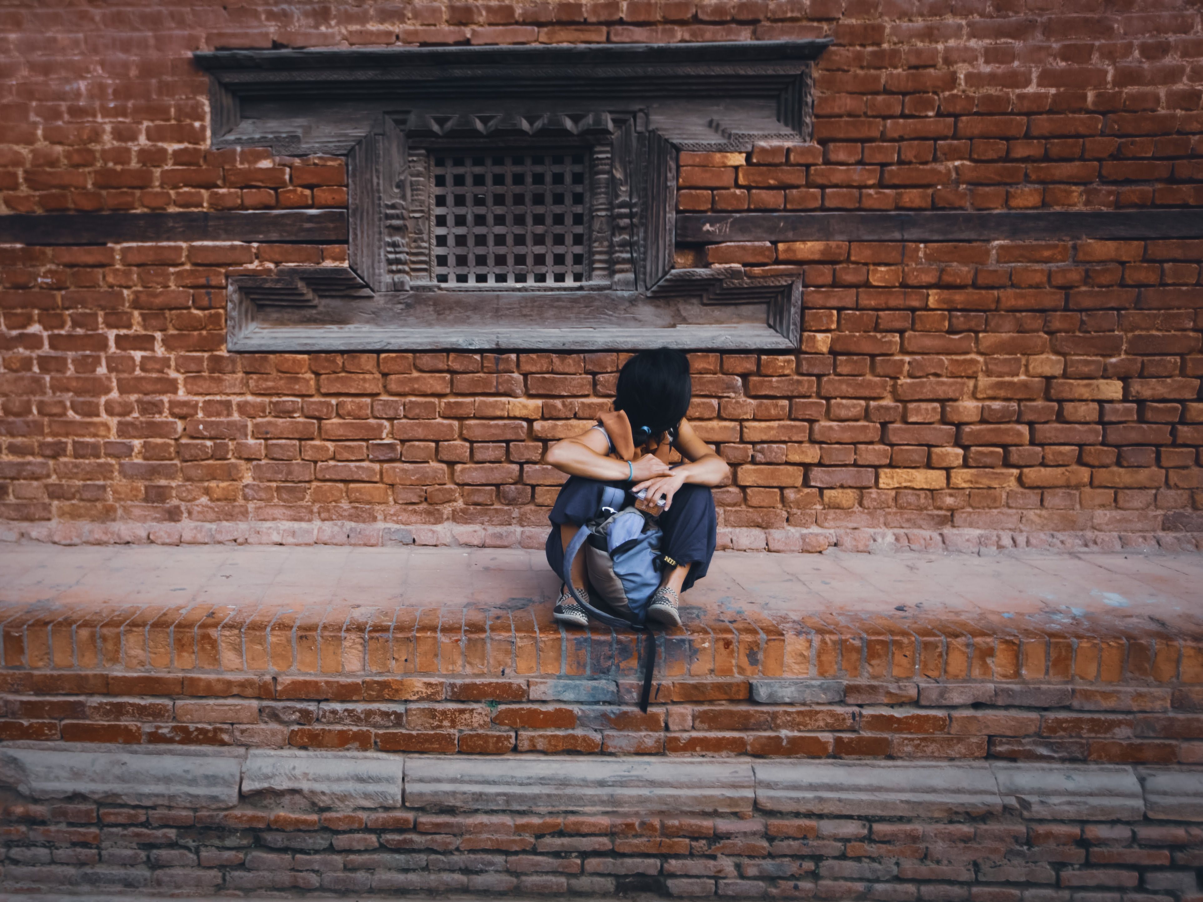 Person with Dark Hair Sitting on a Brick Wall and Looking Behind · Free ...
