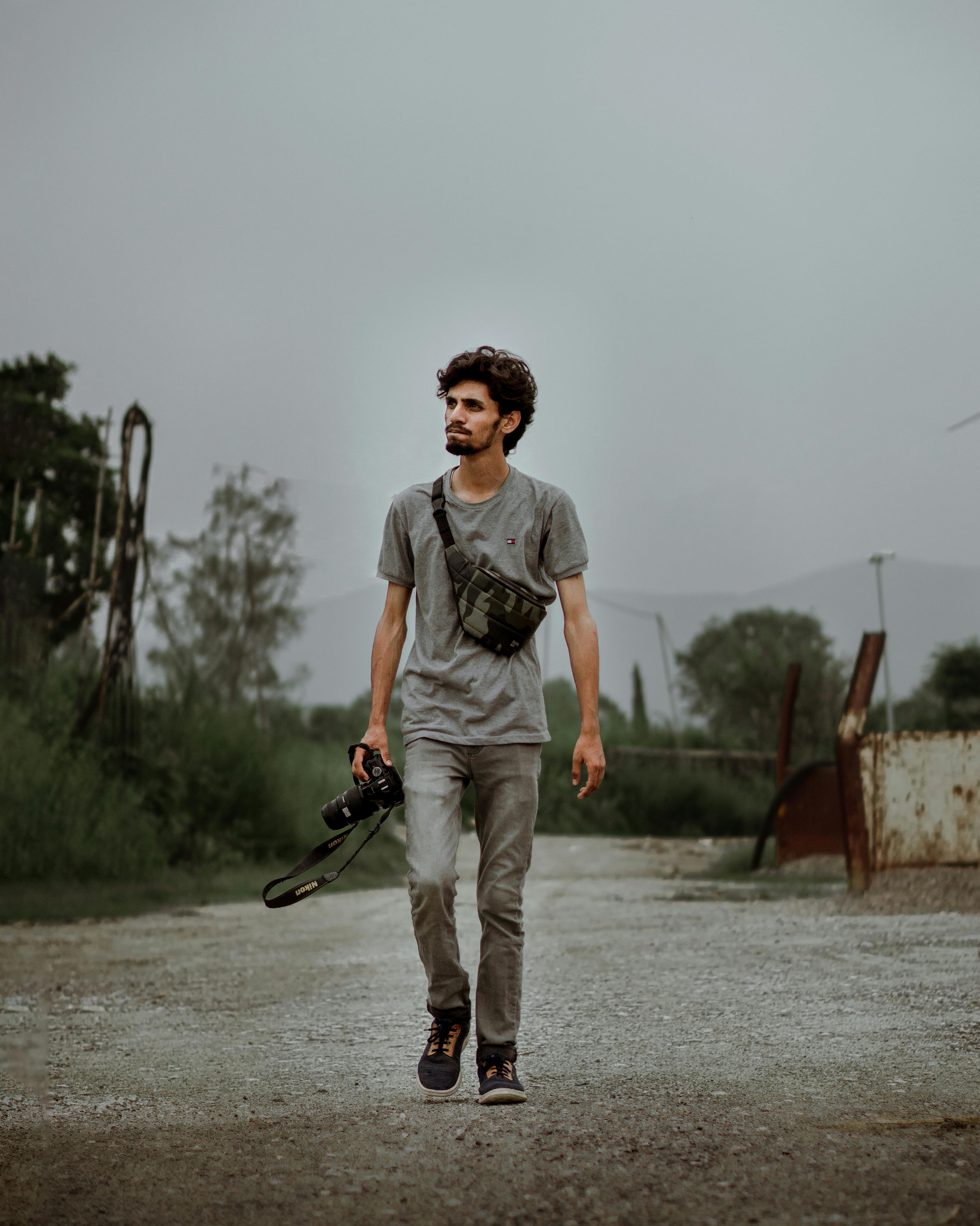 Man Walking wiht a Camera in his Hand · Free Stock Photo