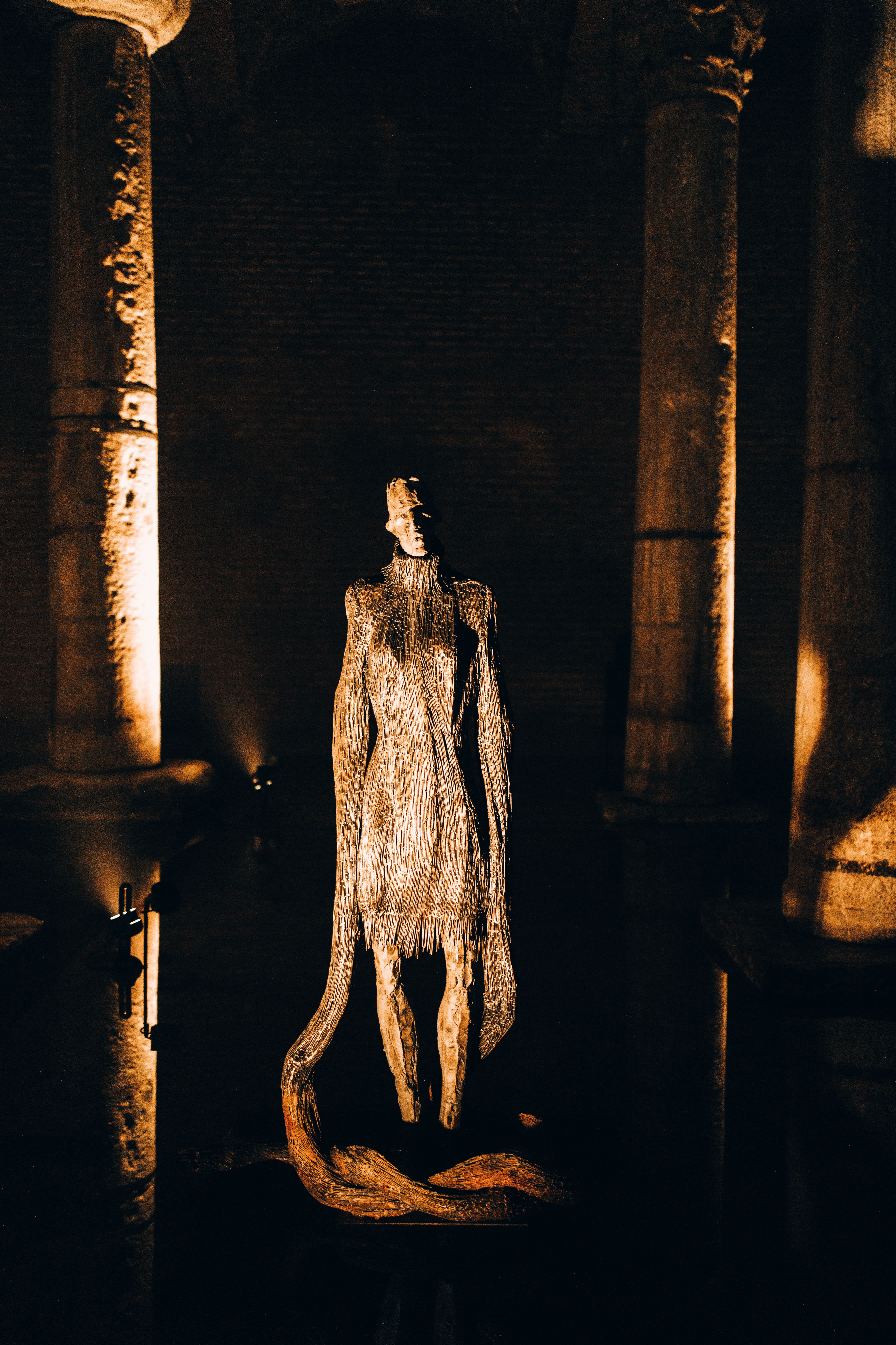 Contemporary Statue Standing Between Ancient Columns · Free Stock Photo