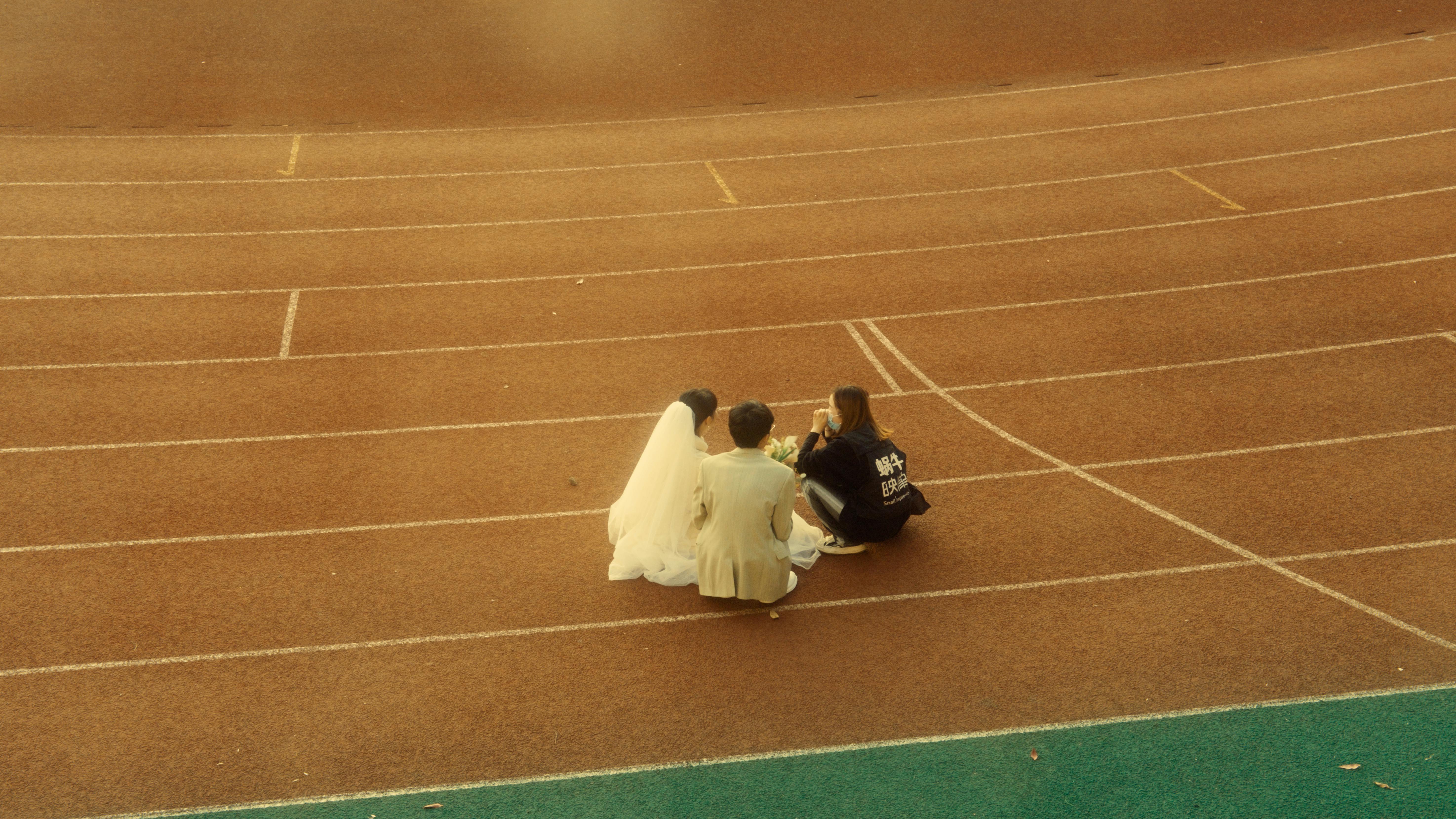 Three People Sitting on a Running Track · Free Stock Photo