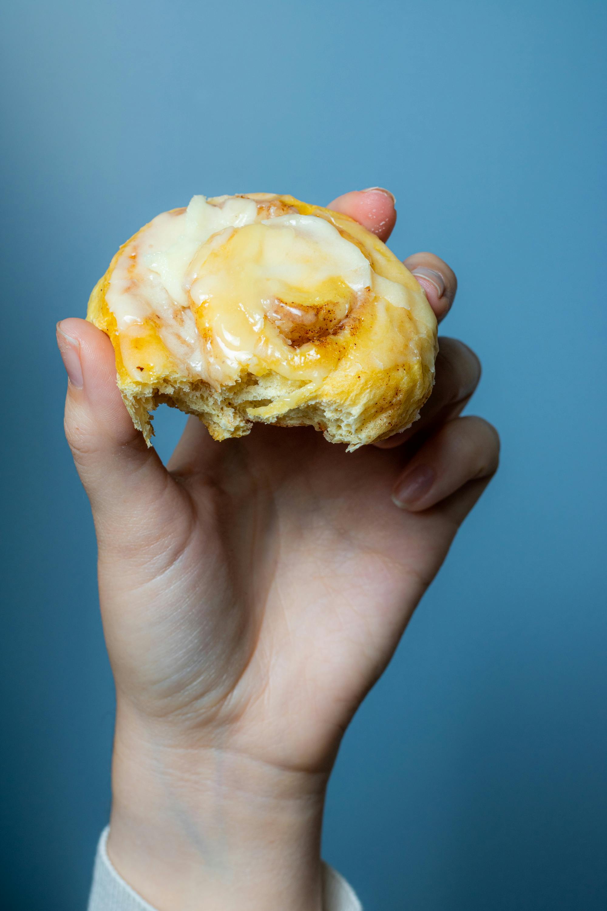 A Person Holding a Cinnamon Roll · Free Stock Photo