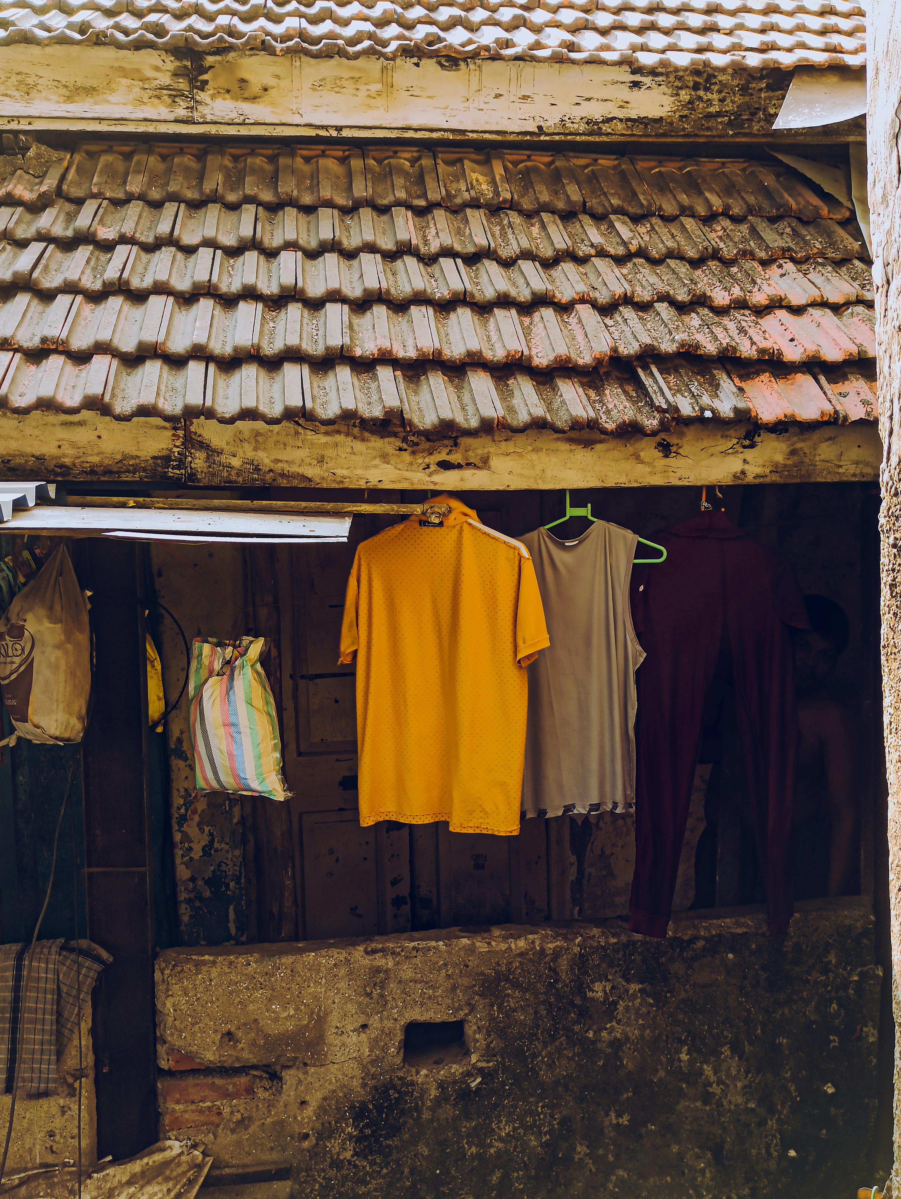 A Yellow Shirt and Gray Tank Top Hanging on the Roof · Free Stock Photo