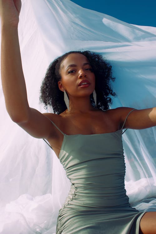 A Woman In Blue Dress Holding White Fabric While Posing At The Camera
