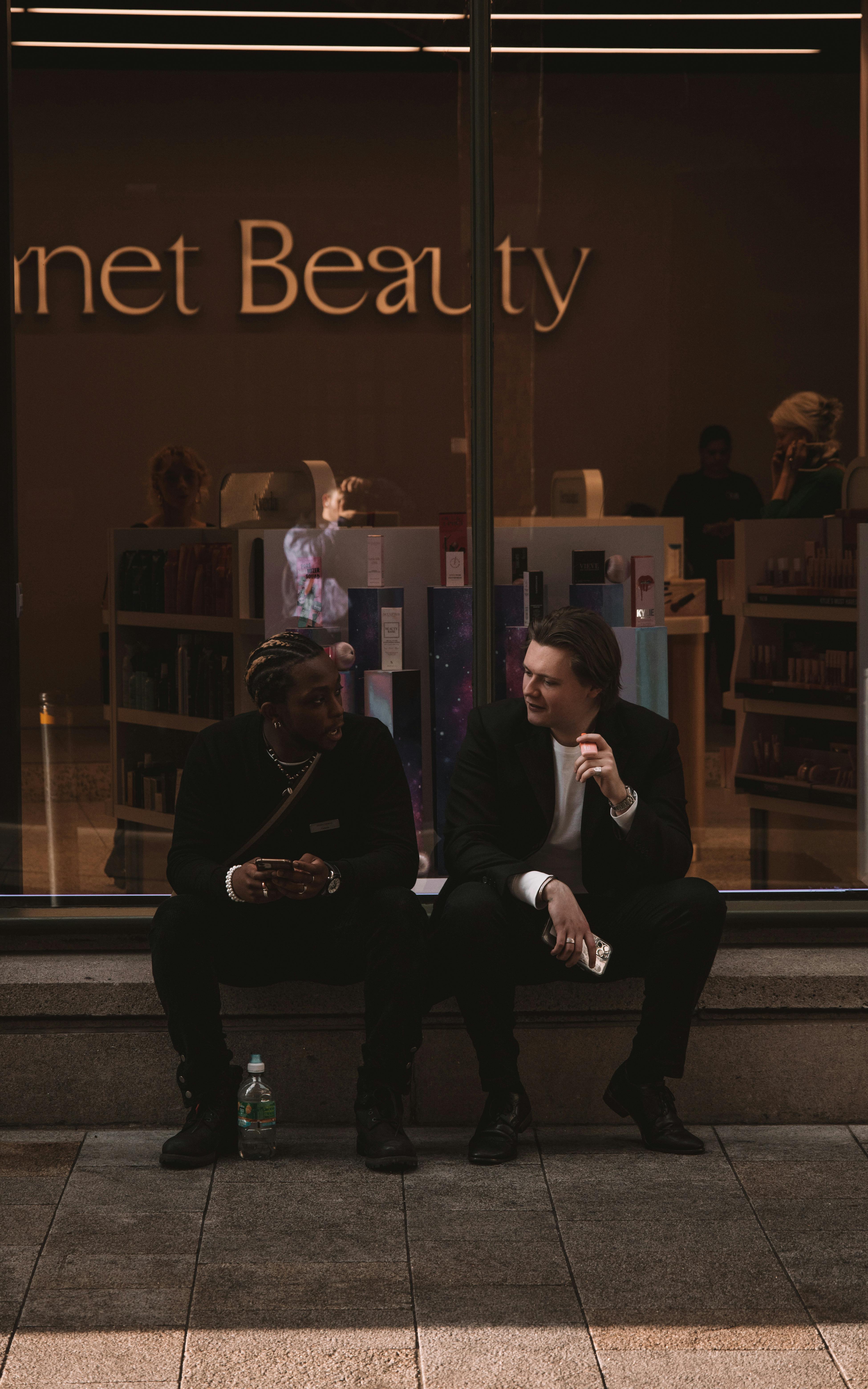 Two Men Sitting Outside a Store · Free Stock Photo