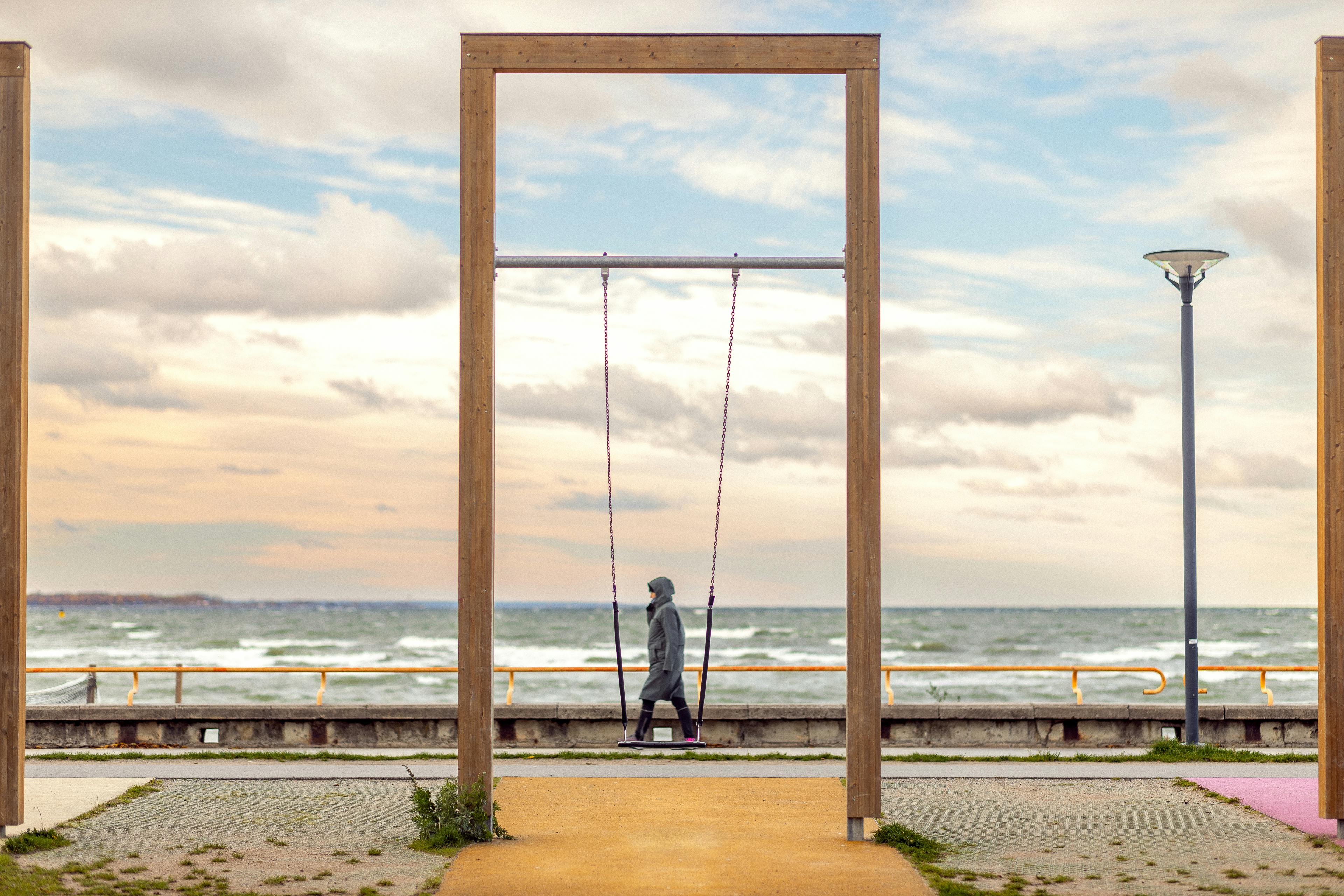 Swing and Woman Walking on Promenade on Sea Shore · Free Stock Photo