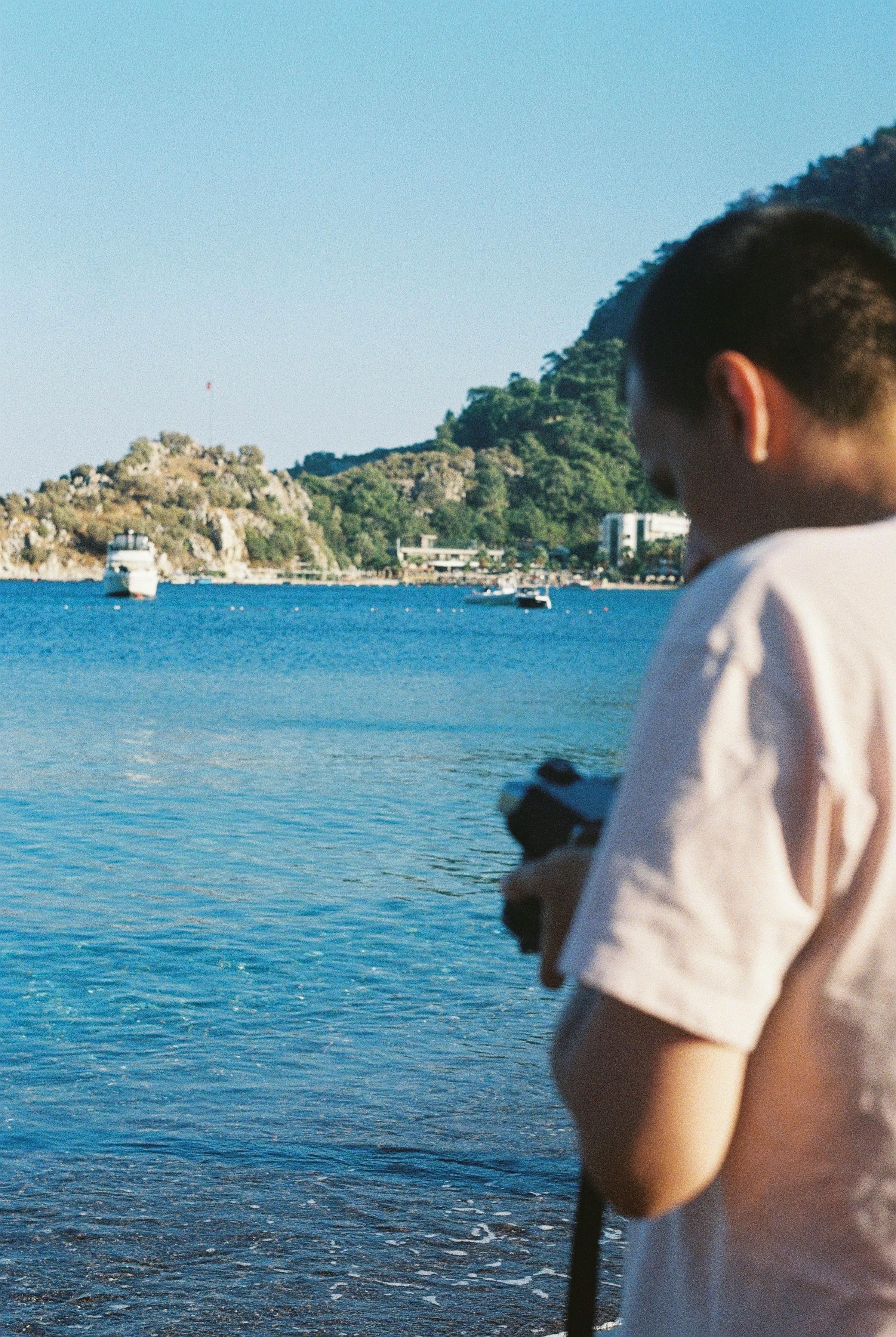Man Looking at His Camera while Standing Near Body of water · Free ...