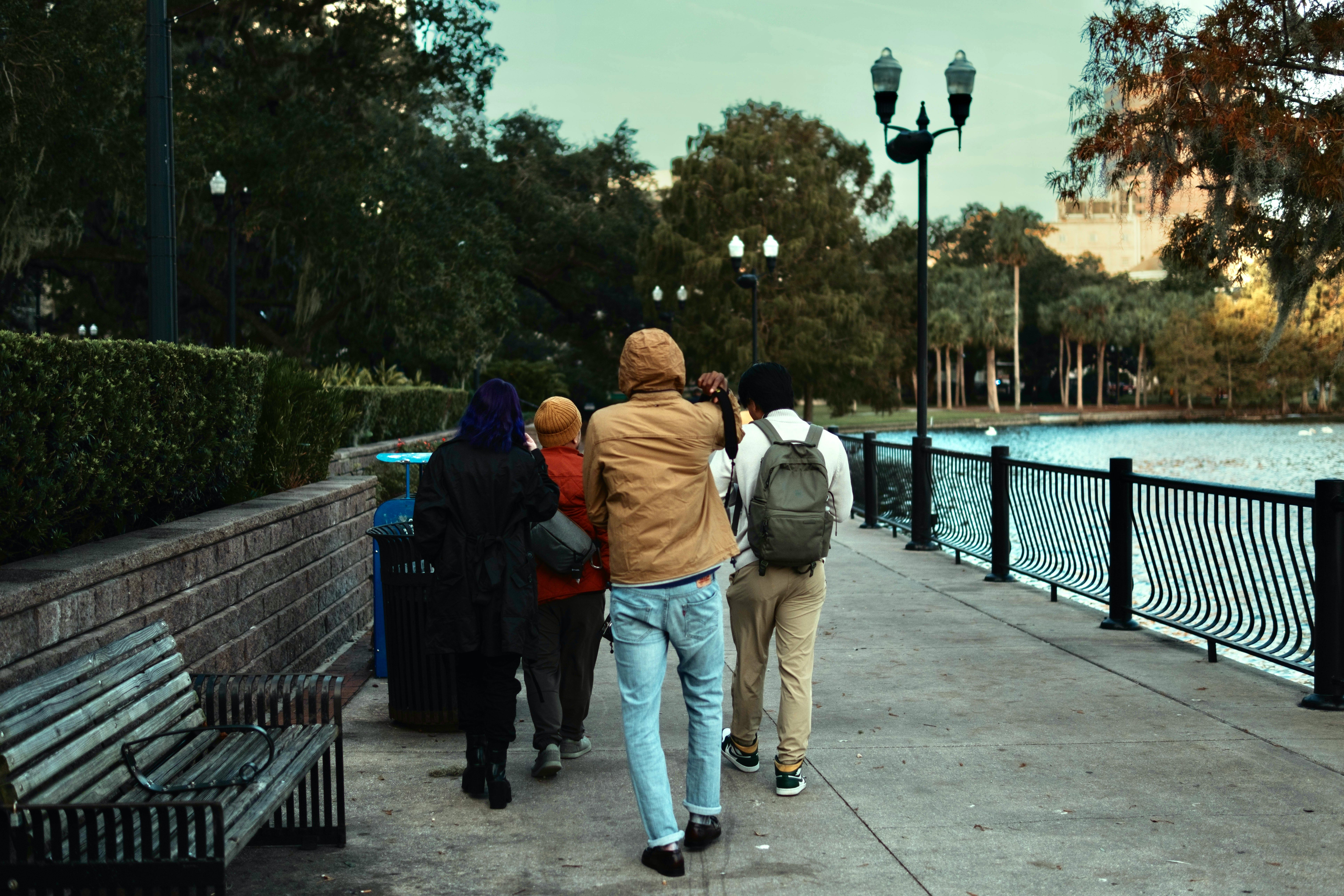 People Walking on Sidewalk Near Lake · Free Stock Photo