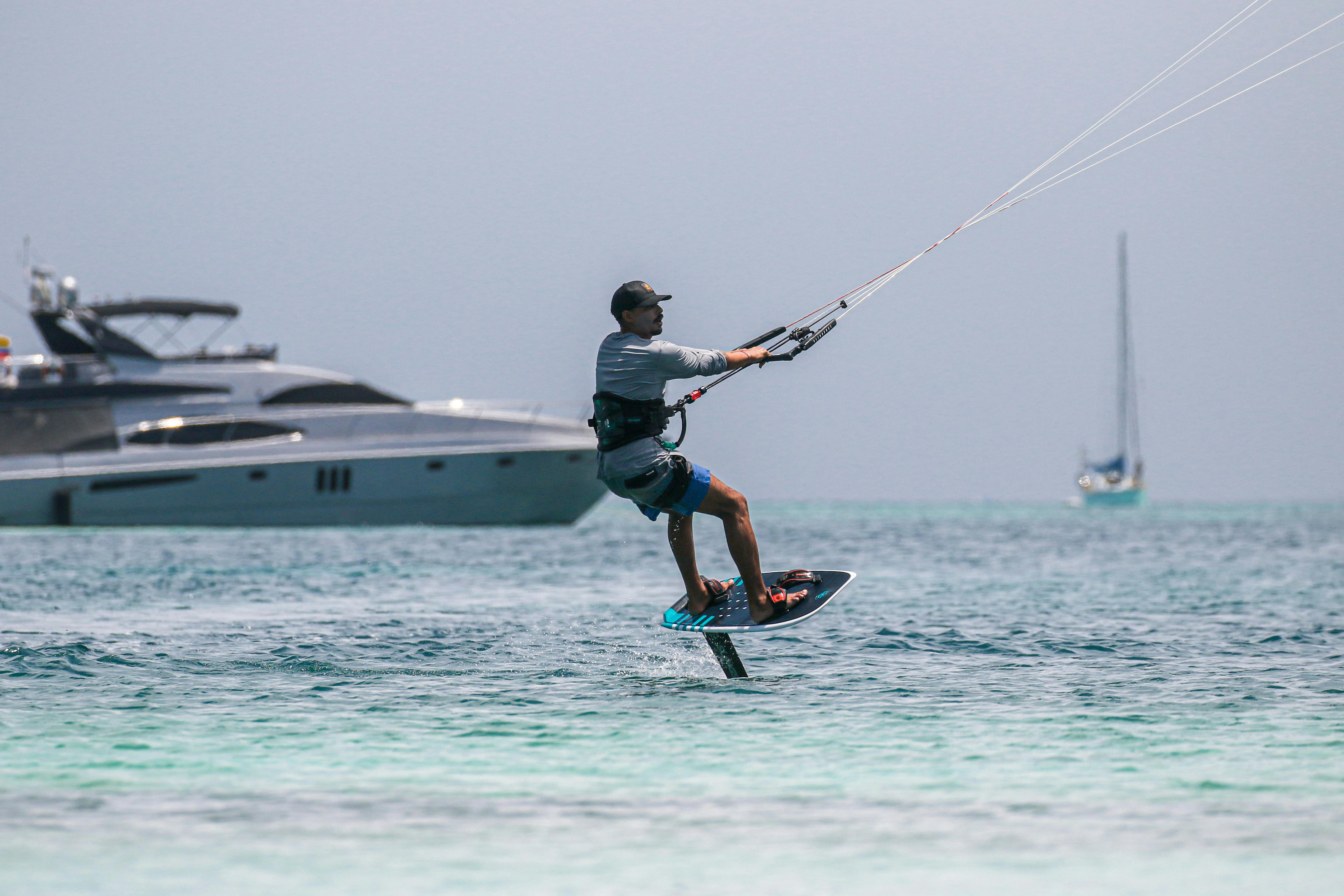 Man Kitesurfing near Boats on the Sea · Free Stock Photo