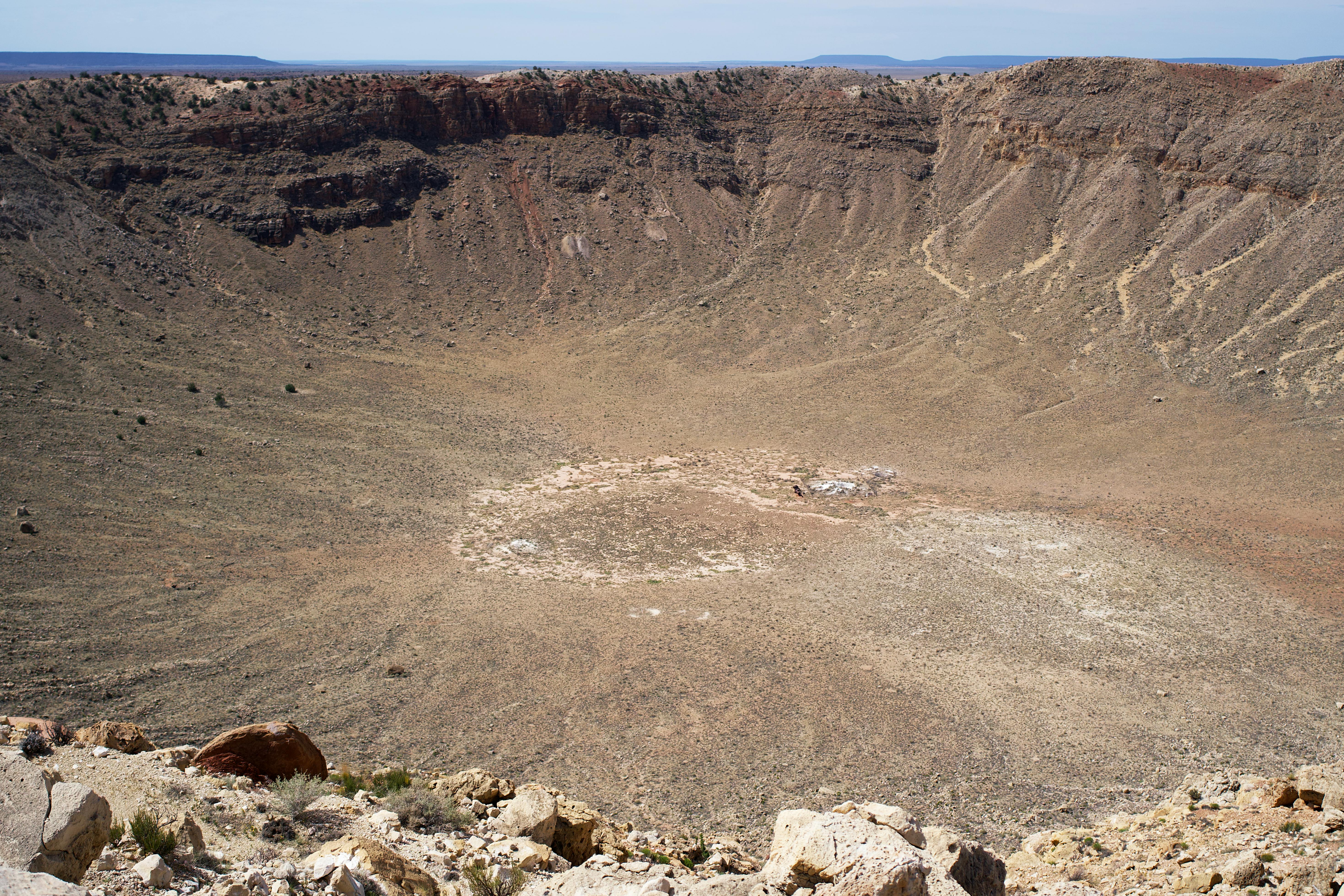 A large crater in the desert with a small hill · Free Stock Photo