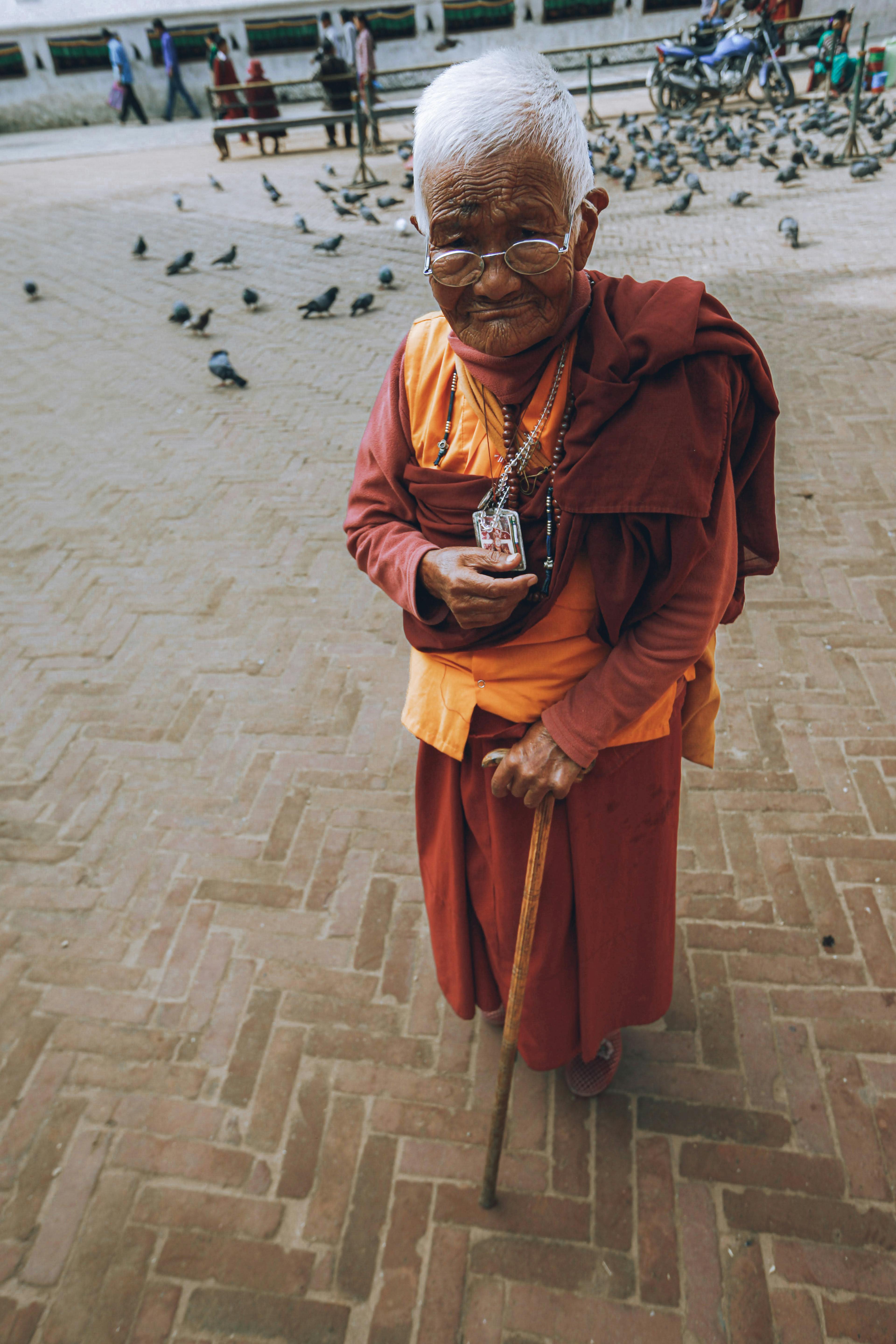 Elderly Woman Donating Food to Monks on Street · Free Stock Photo