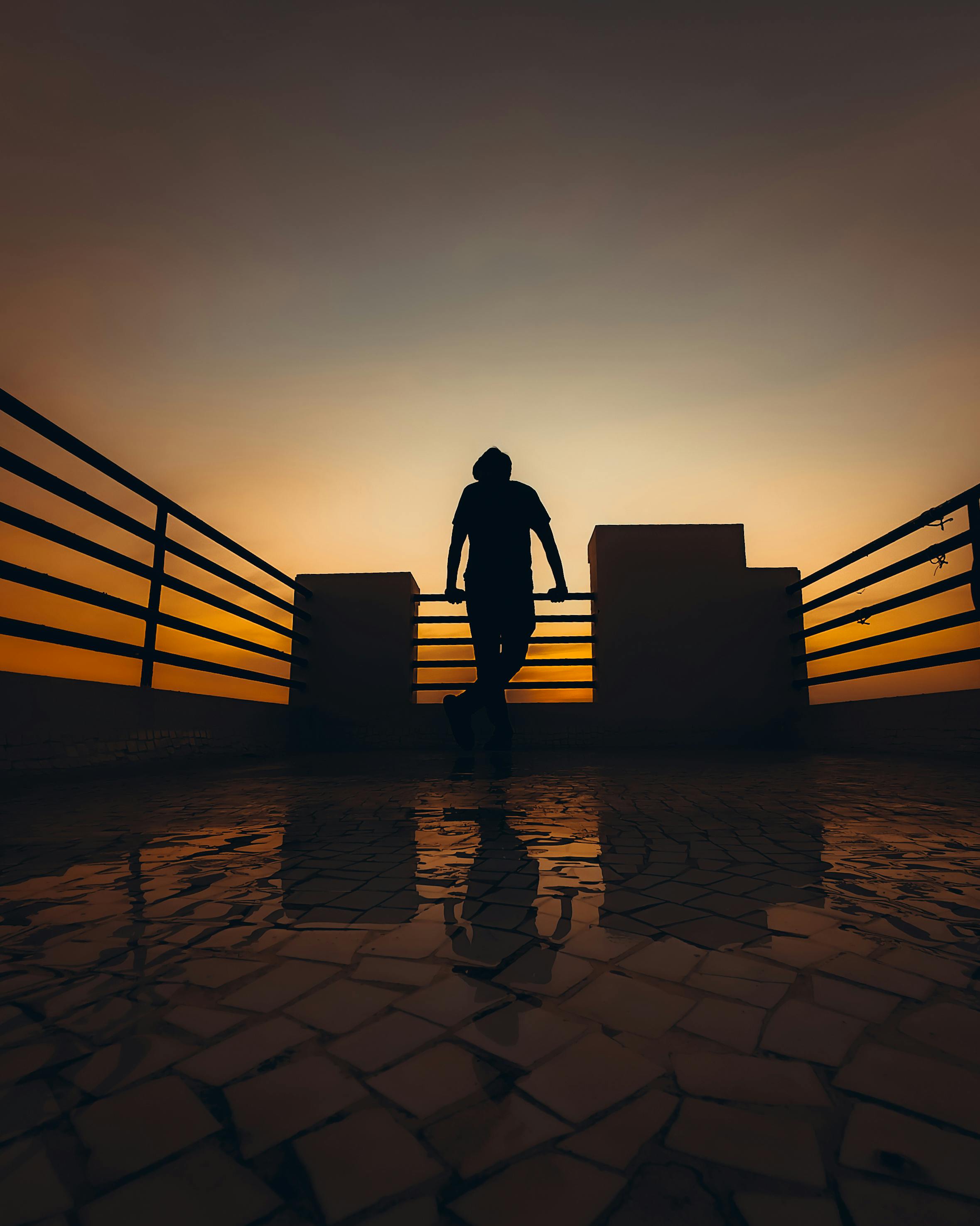 Silhouette of Person Standing on Terrace at Sunset · Free Stock Photo