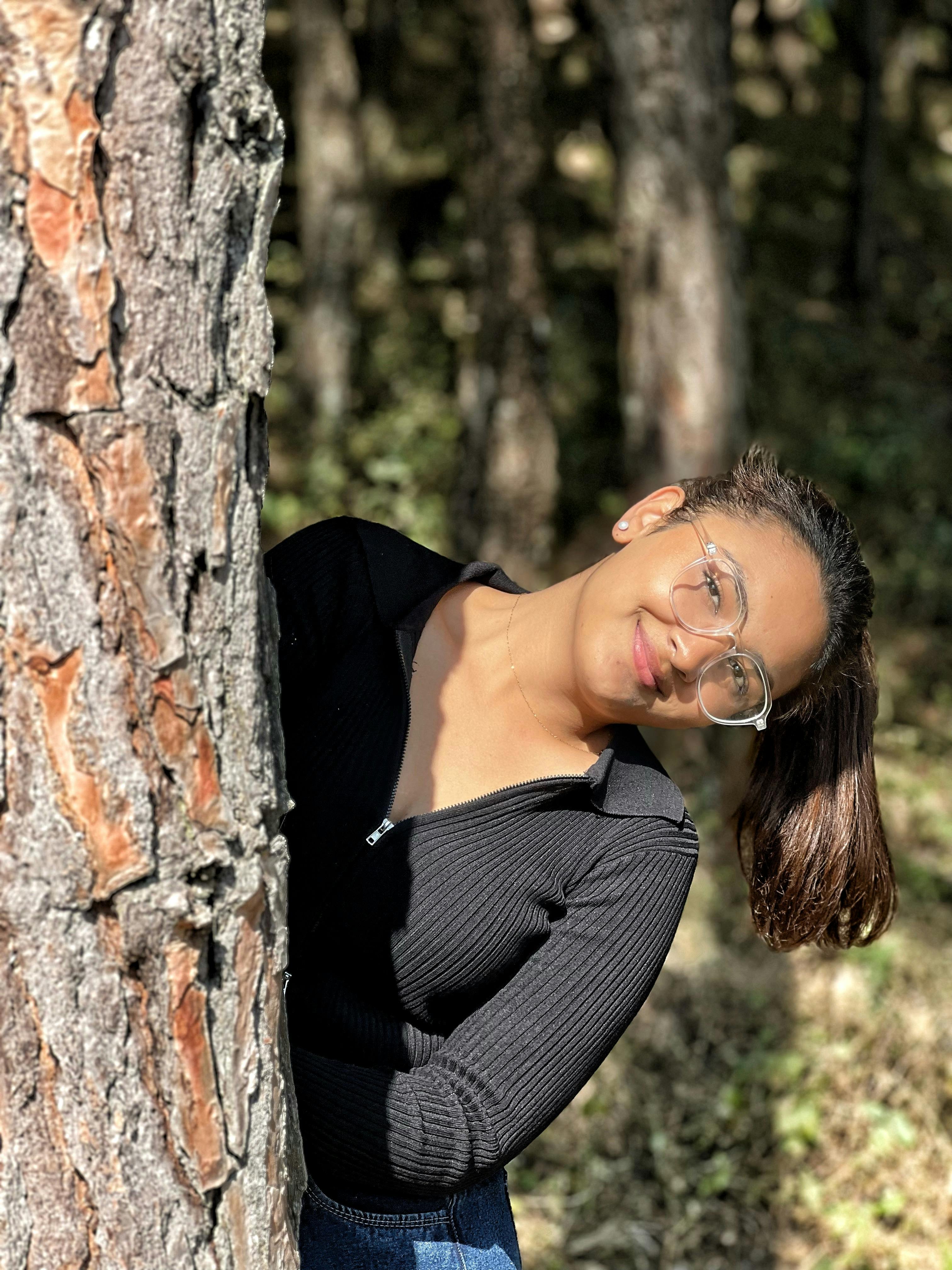 A Woman Standing Behind a Tree while Smiling at the Camera · Free Stock ...
