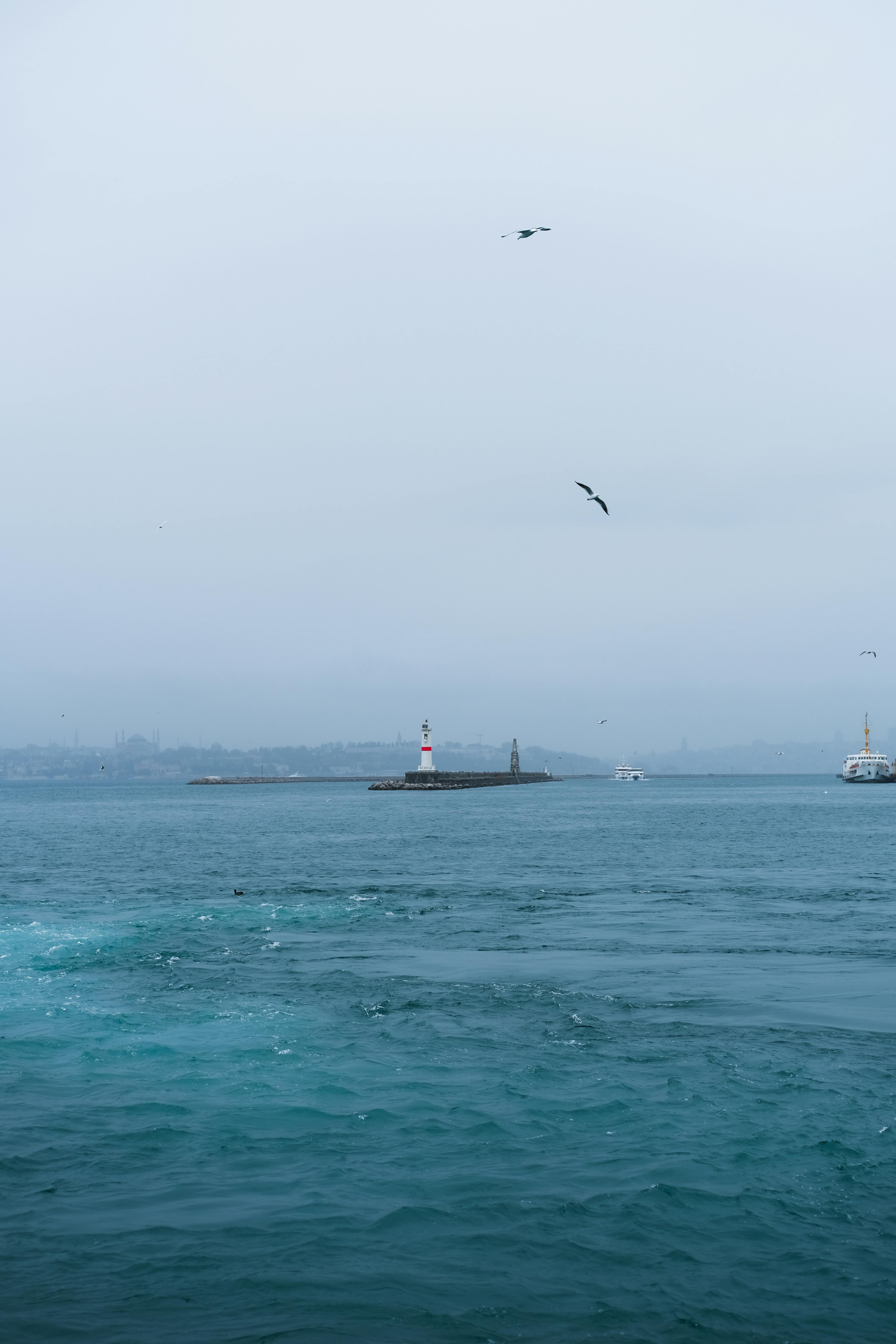 Ships in the Sea with a Lighthouse in the Distance · Free Stock Photo