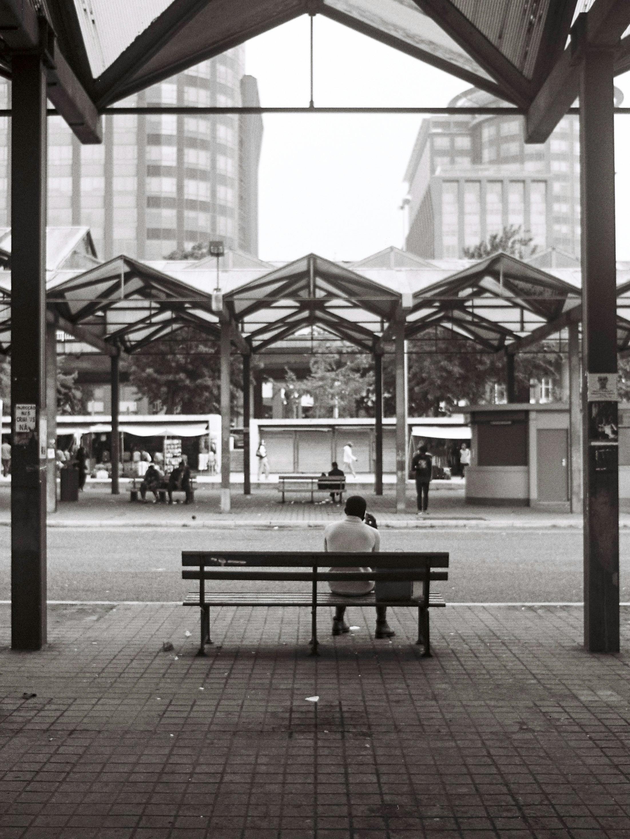 Person Sitting on Bench at Bus Terminal · Free Stock Photo