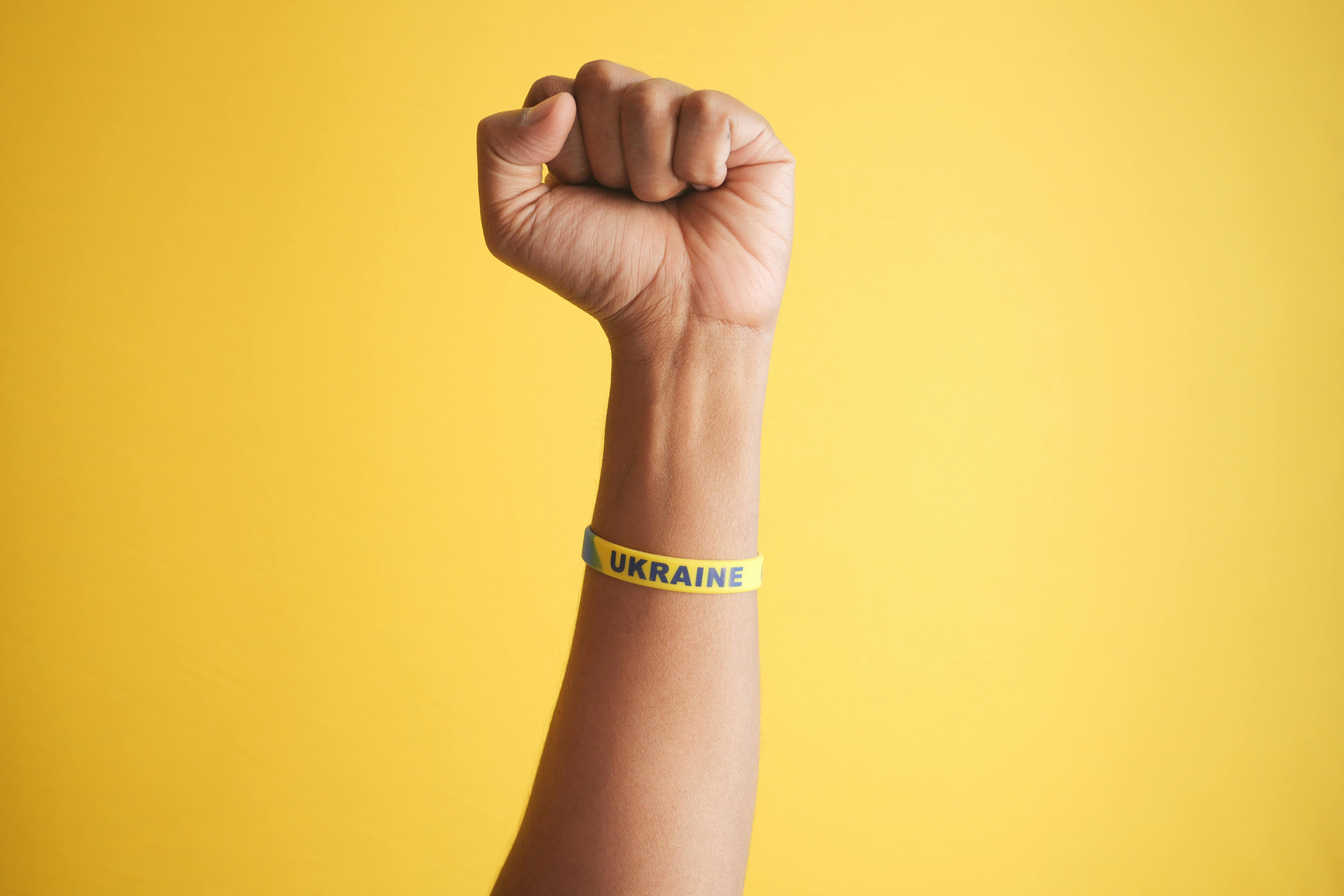 Fist Raised in Air on Yellow Back · Free Stock Photo