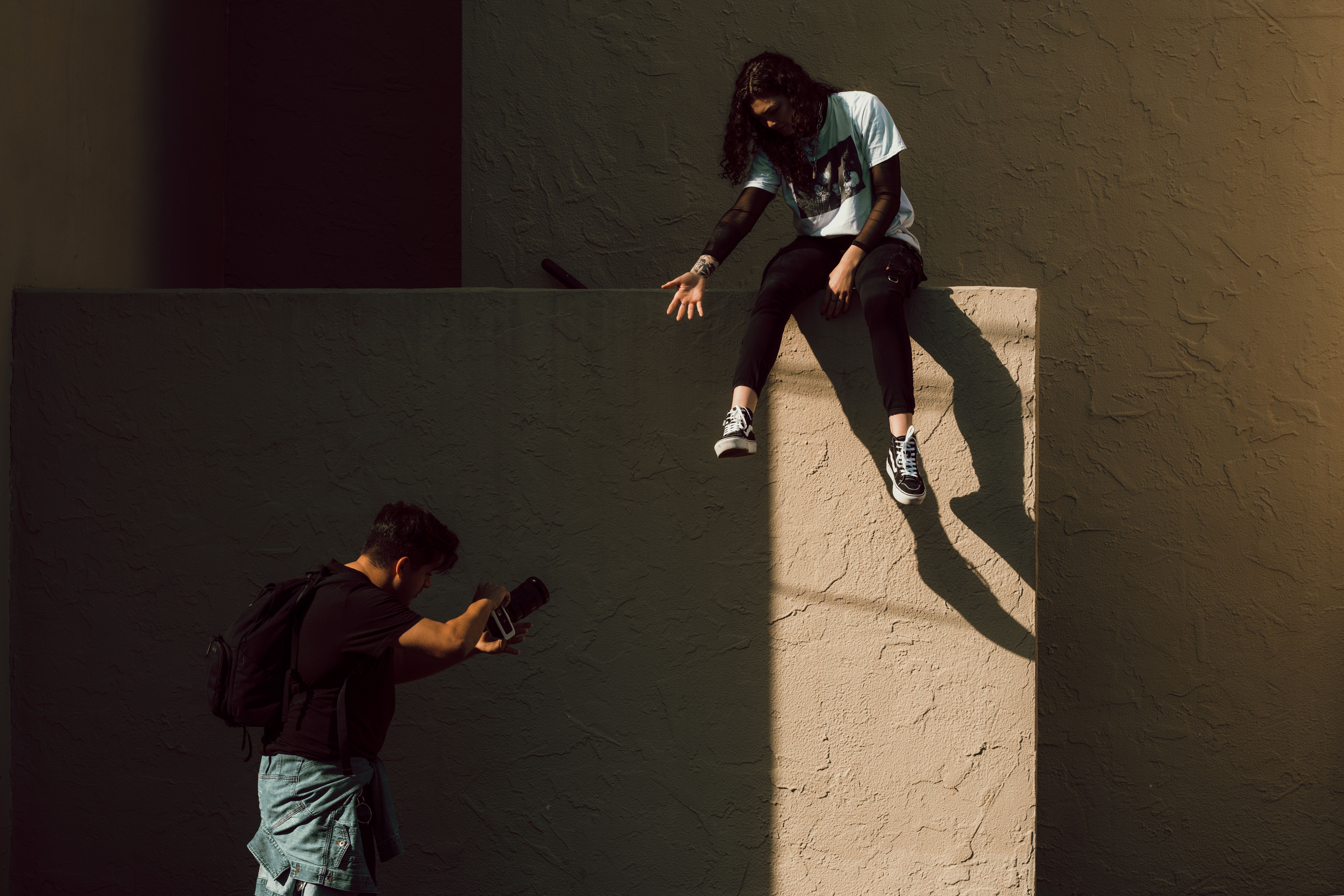 A Photographer Taking a Picture of a Woman Sitting on a Concrete Wall ...